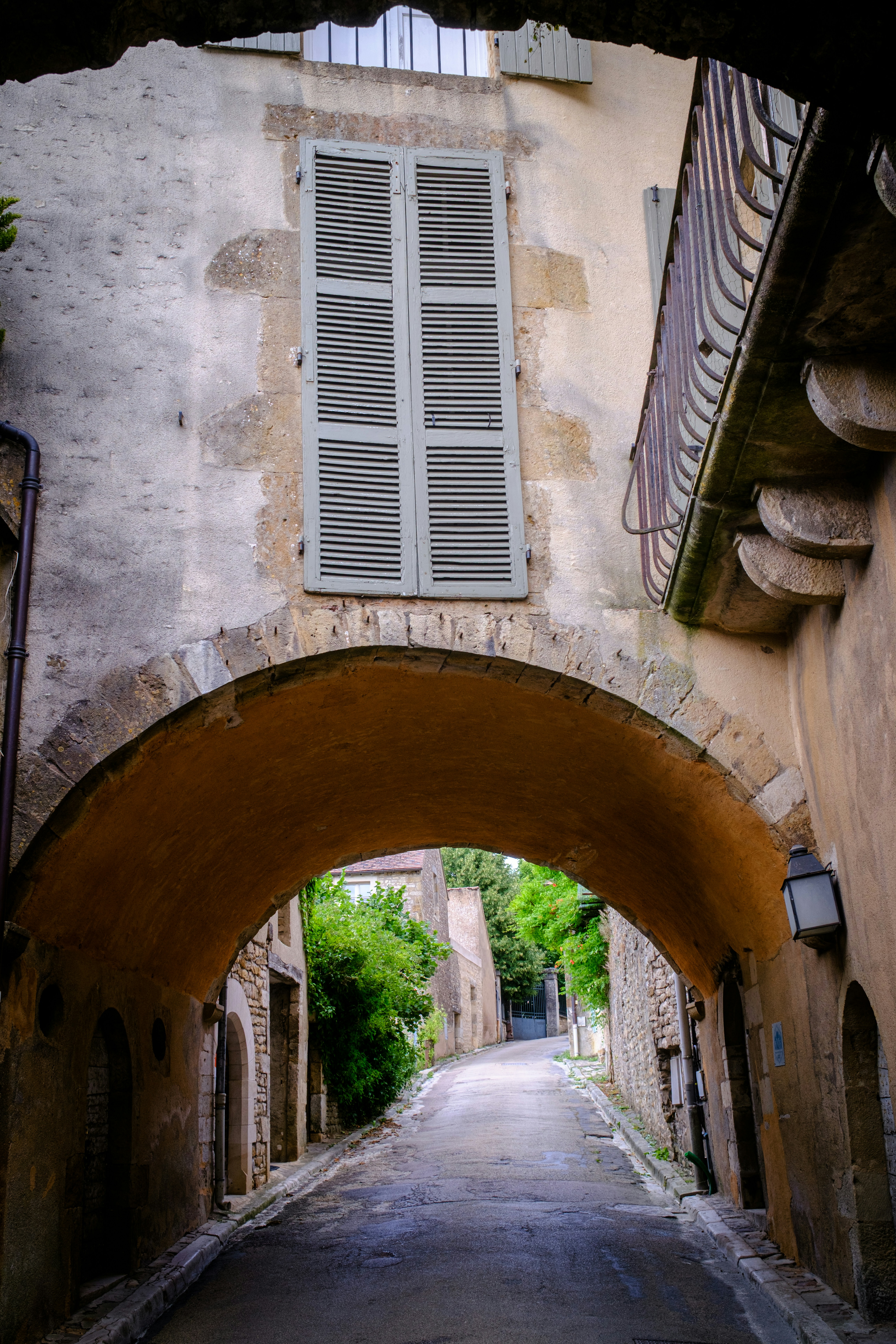 Vézelay, a hilltop commune in Bourgogne-Franche-Comté, France, is renowned for its UNESCO-listed Basilica of St. Magdalene. With origins dating back to prehistoric settlements, it flourished in the Middle Ages as a pilgrimage center and crusade rallying point. Today, it remains notable for history, architecture, and Chardonnay-based wine production. | Stone archway over a cobblestone street in a village
