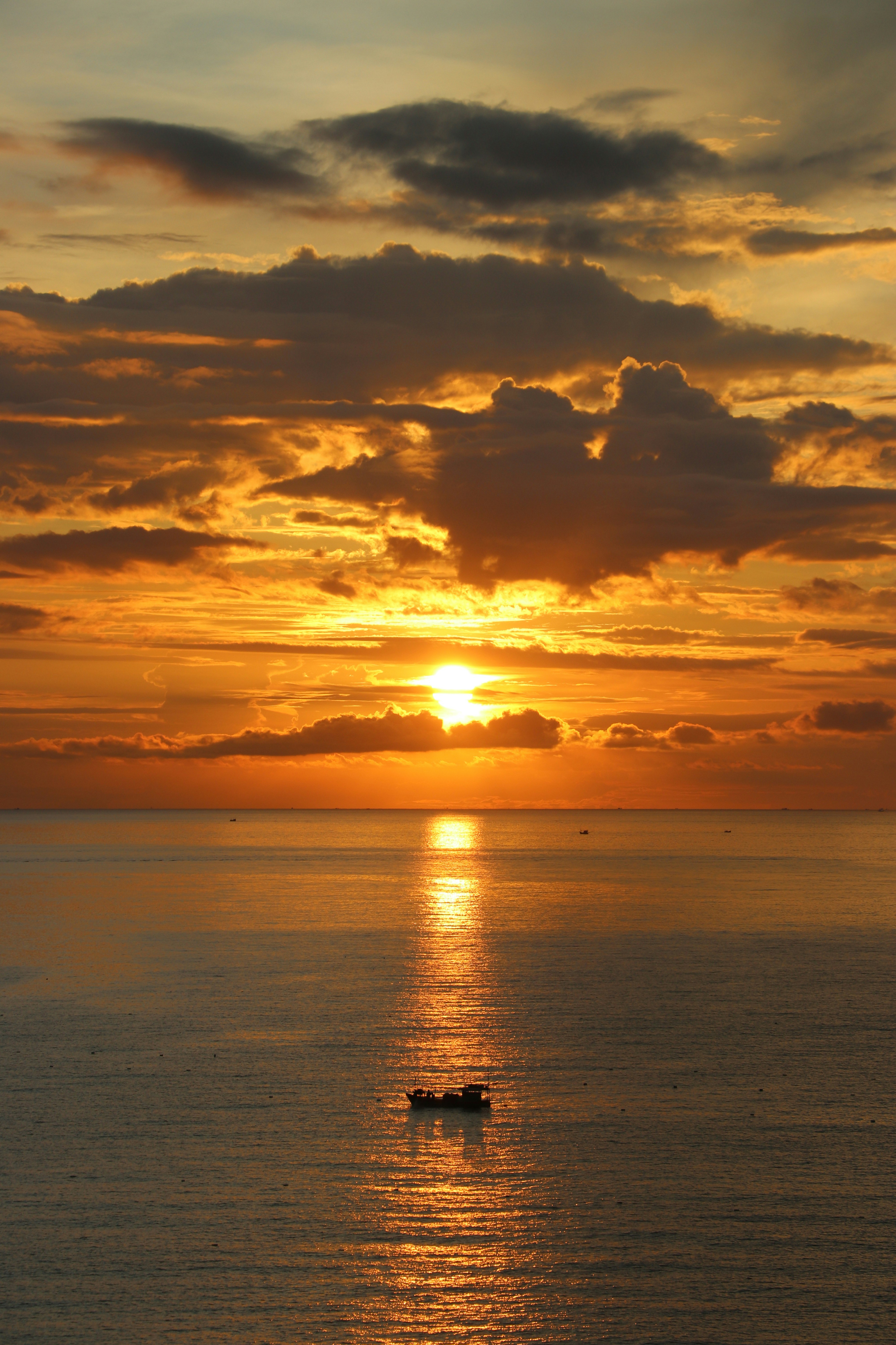 A lone boat on the ocean at sunset.