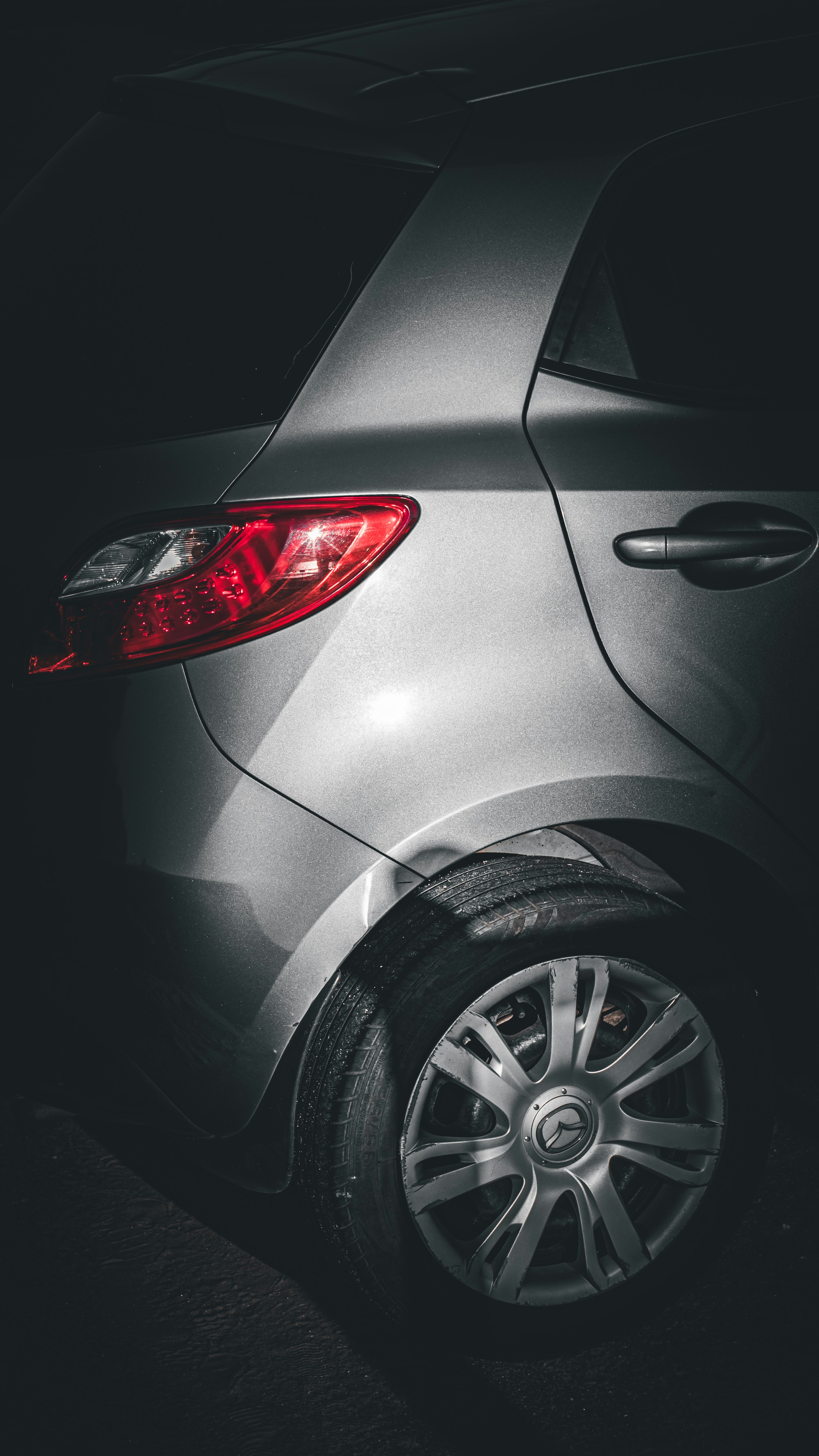 Close up of a silver car's rear taillight and wheel