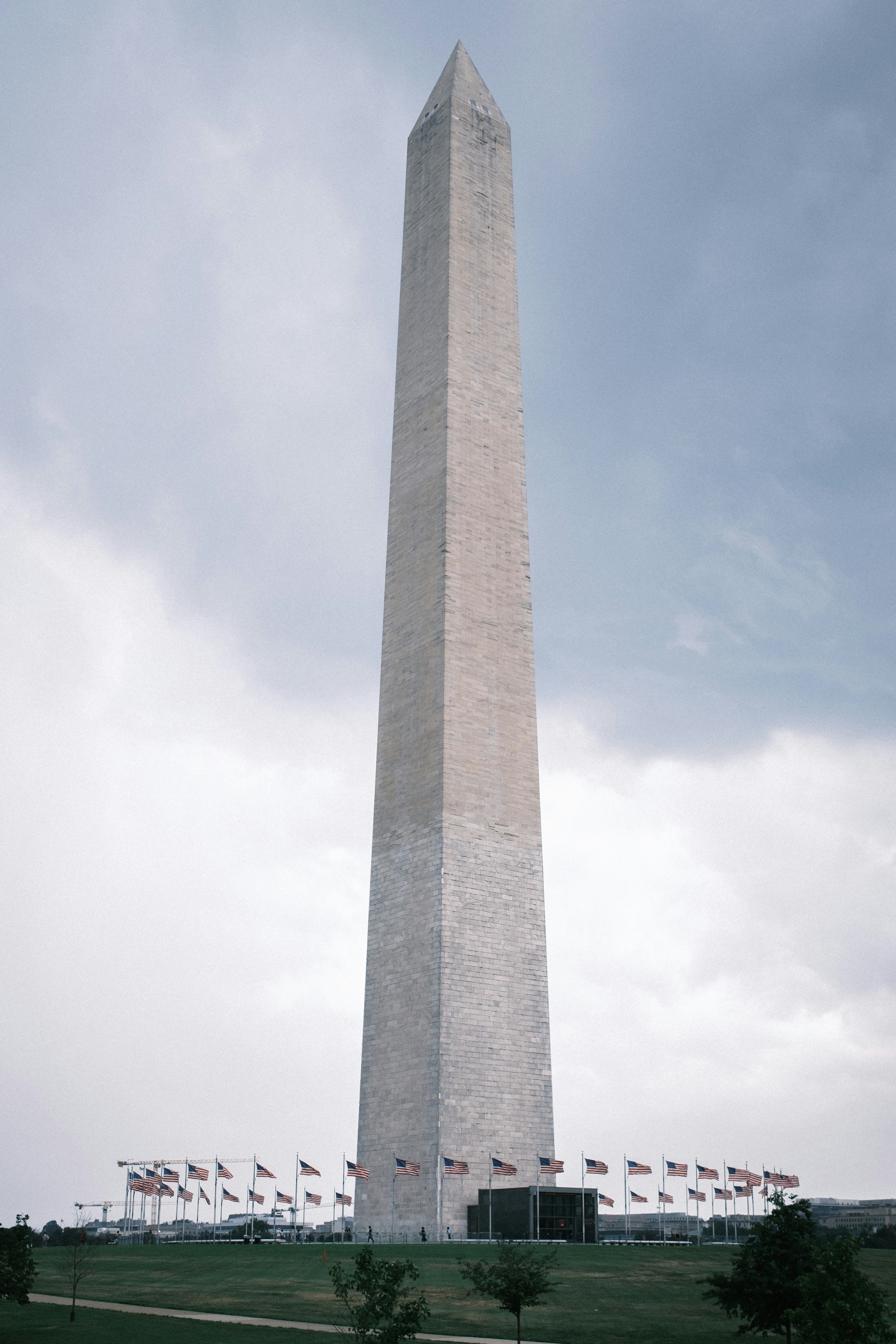 Washington monument surrounded by flags under cloudy sky