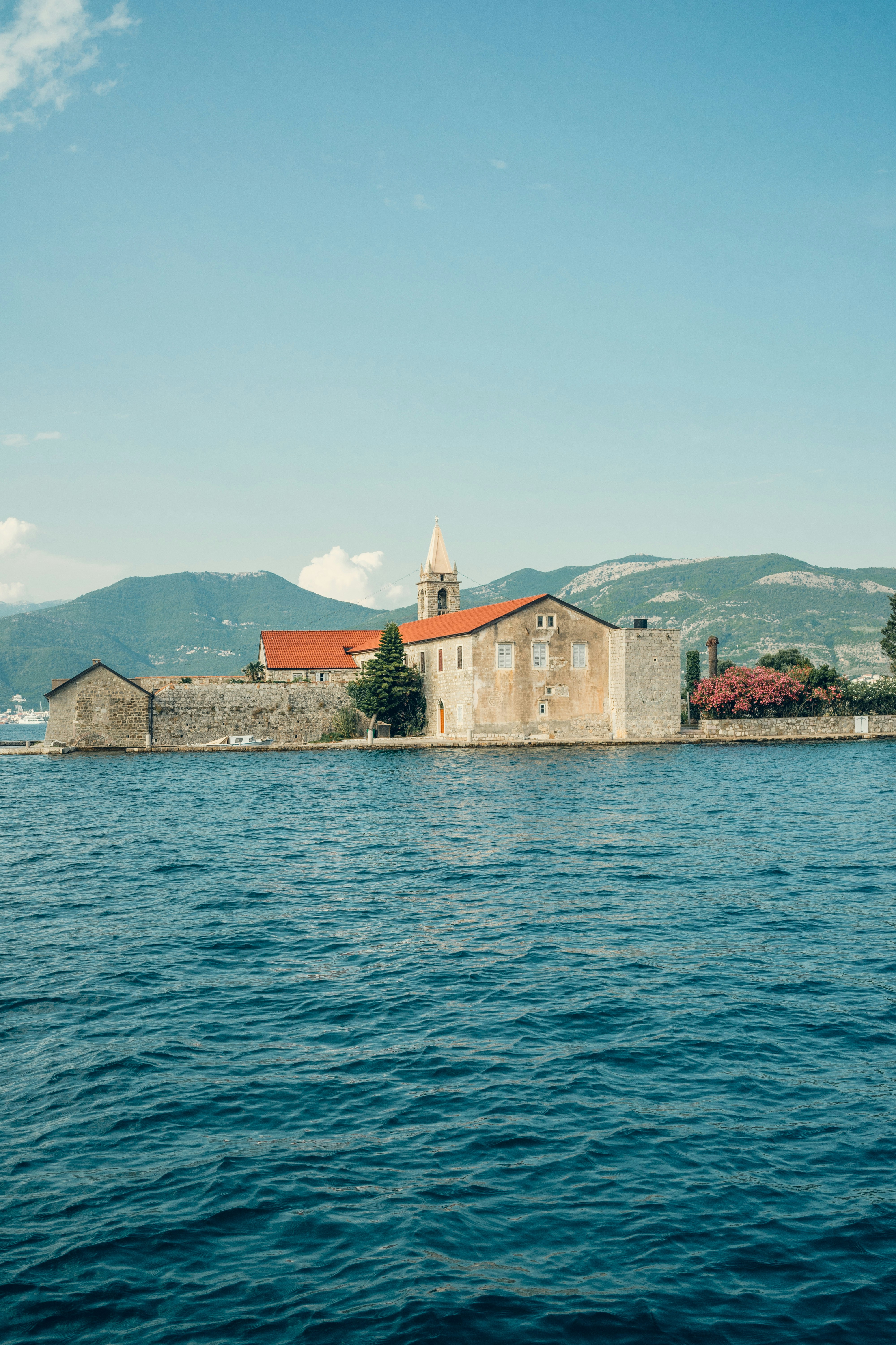 Historic stone buildings on an island with mountains behind.