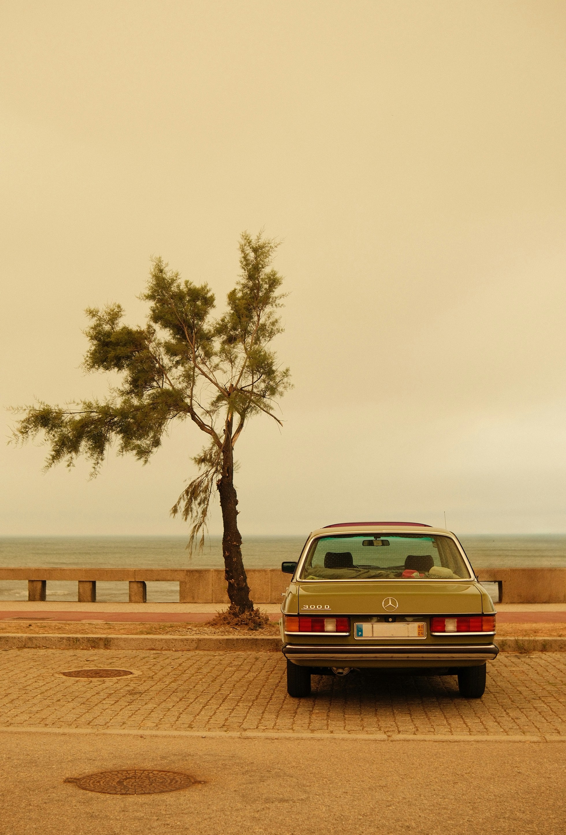 Seaside | Vintage car parked by the sea under a hazy sky