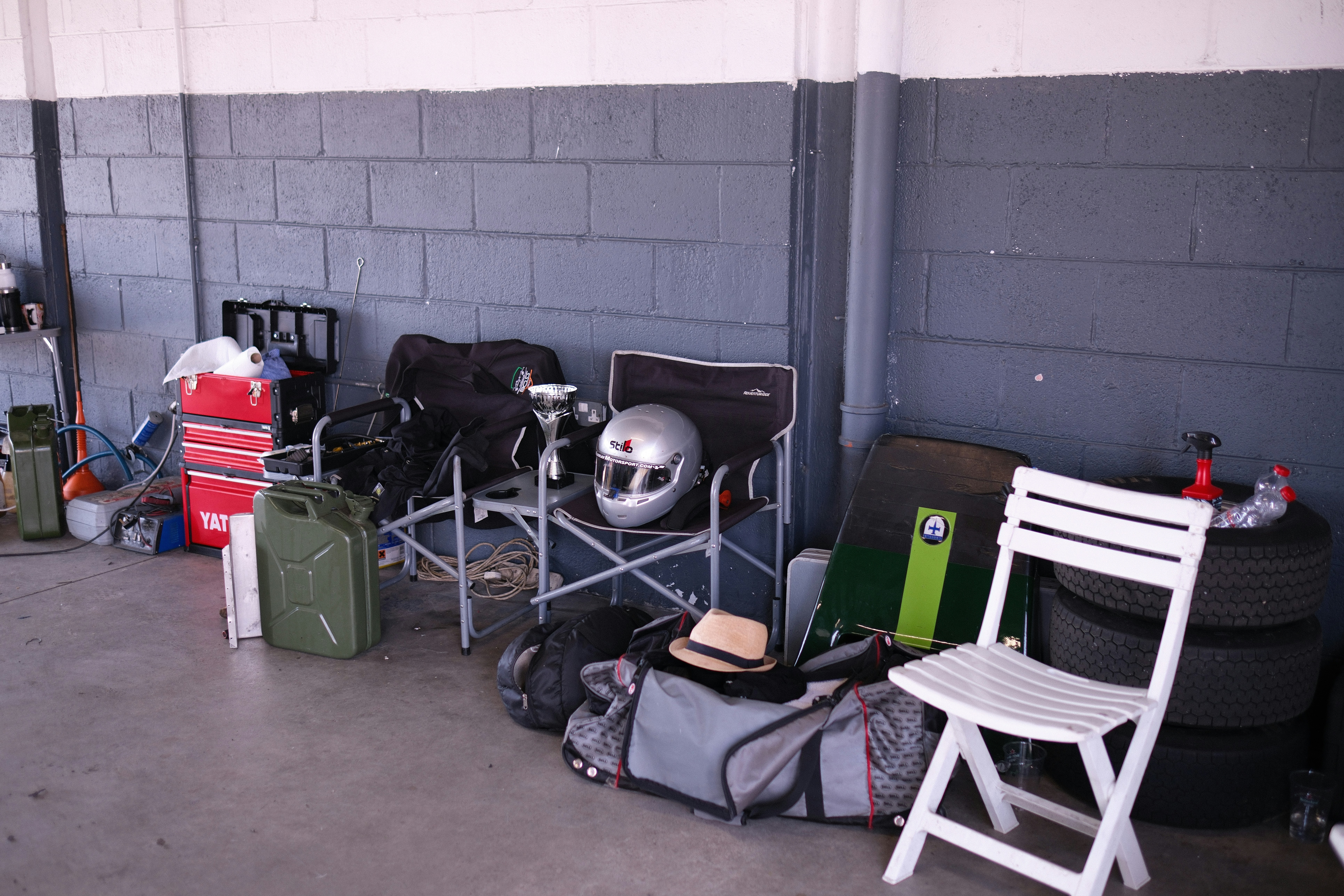 A collection of racing gear and equipment, including a helmet and tools, arranged in a garage setting. The scene captures the essence of motorsport preparation.