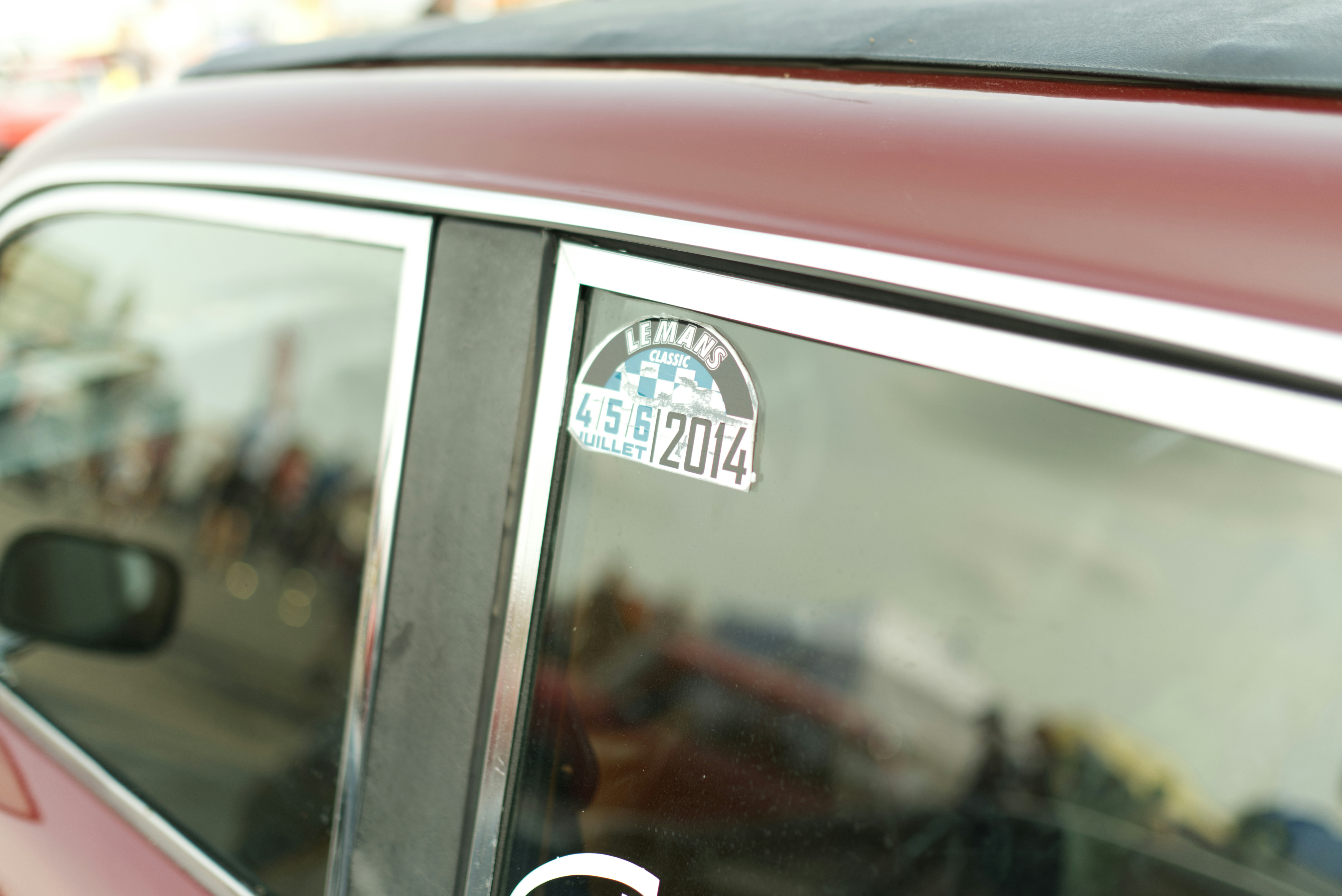Le Mans 2014 sticker on a red car window, framed by chrome trim