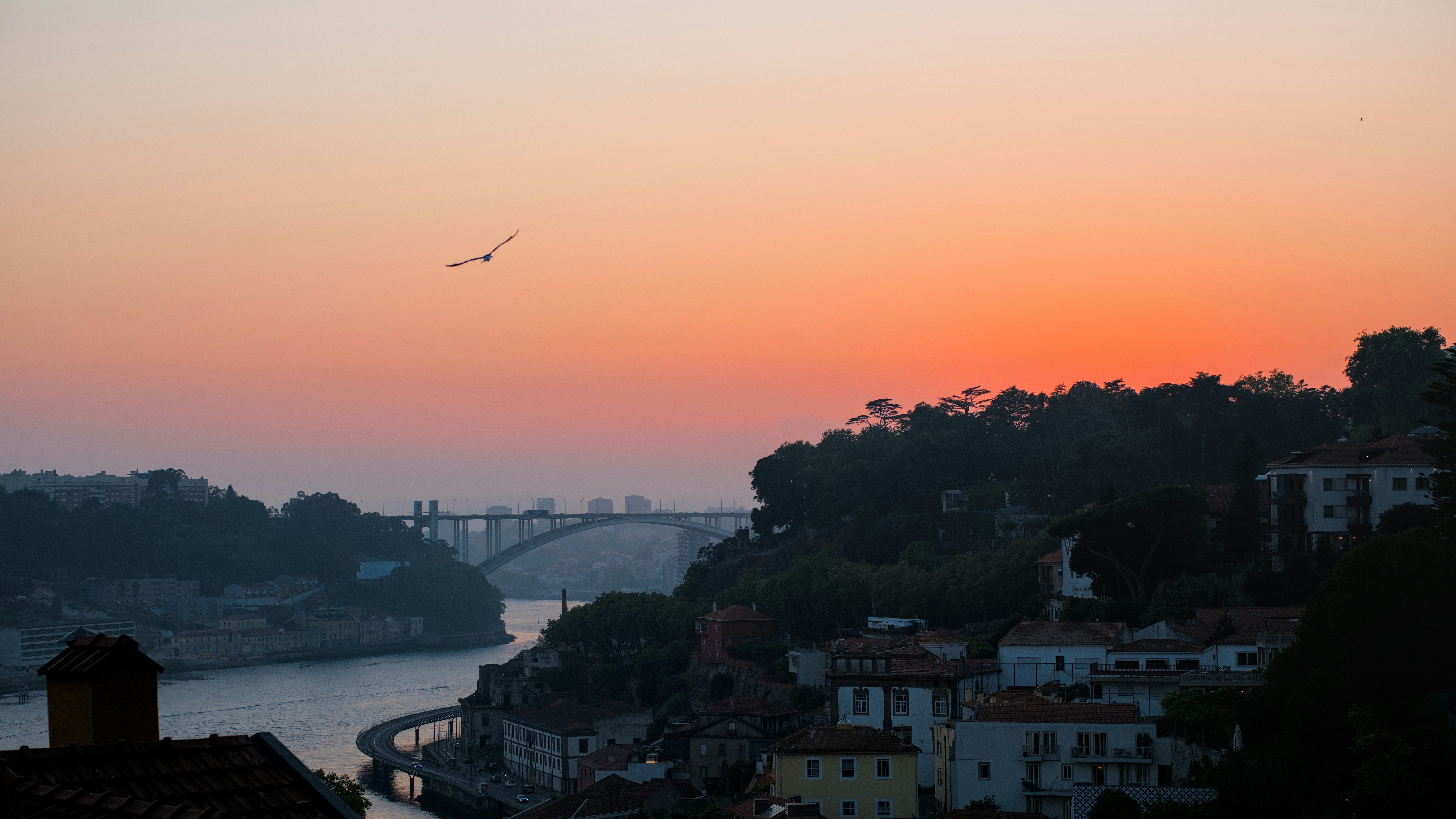 Dawn Over the Glassy River: A Quiet Coastal Town Beneath an Orange Horizon