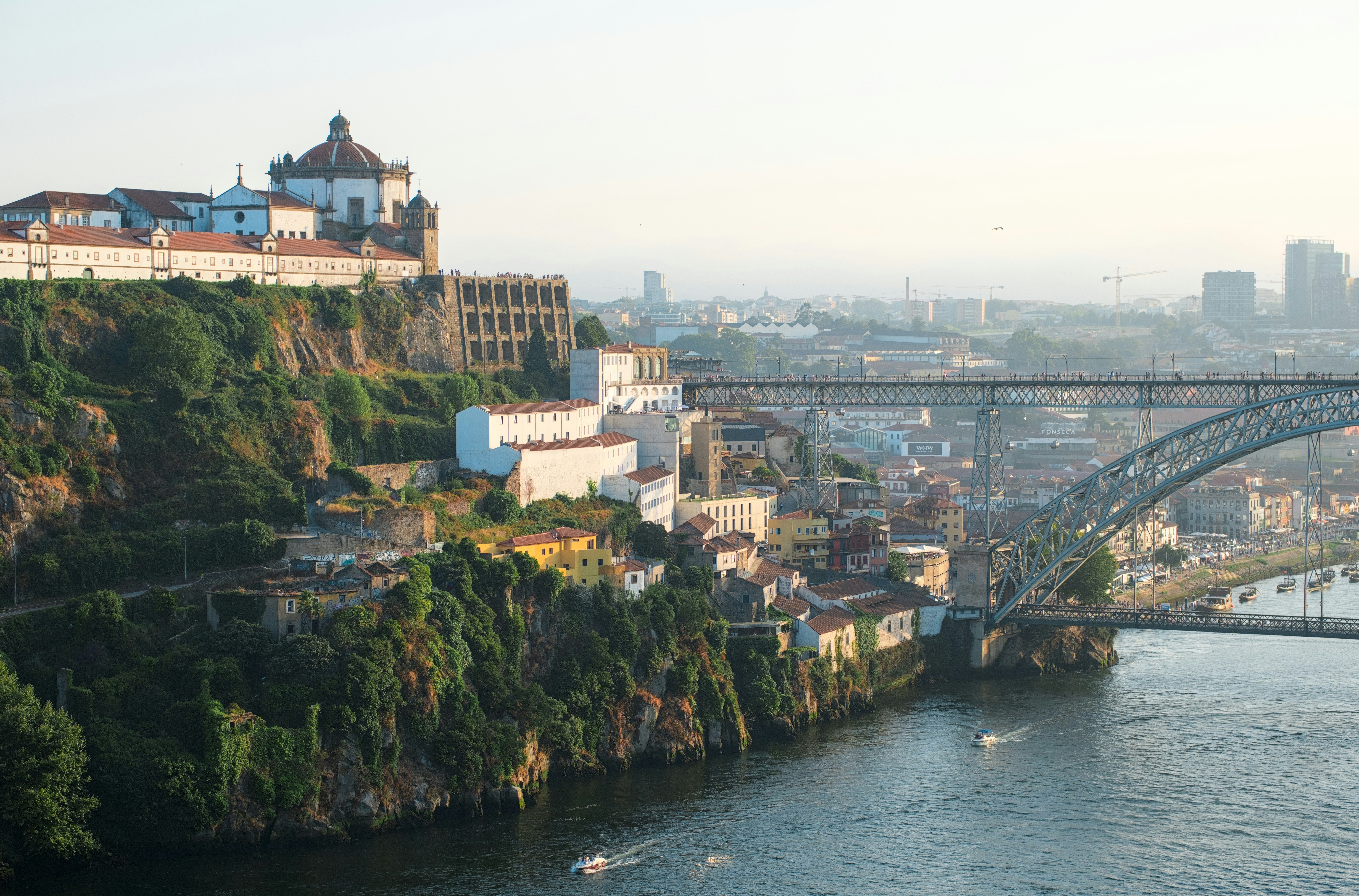 Historic buildings overlook a wide river with a large bridge.