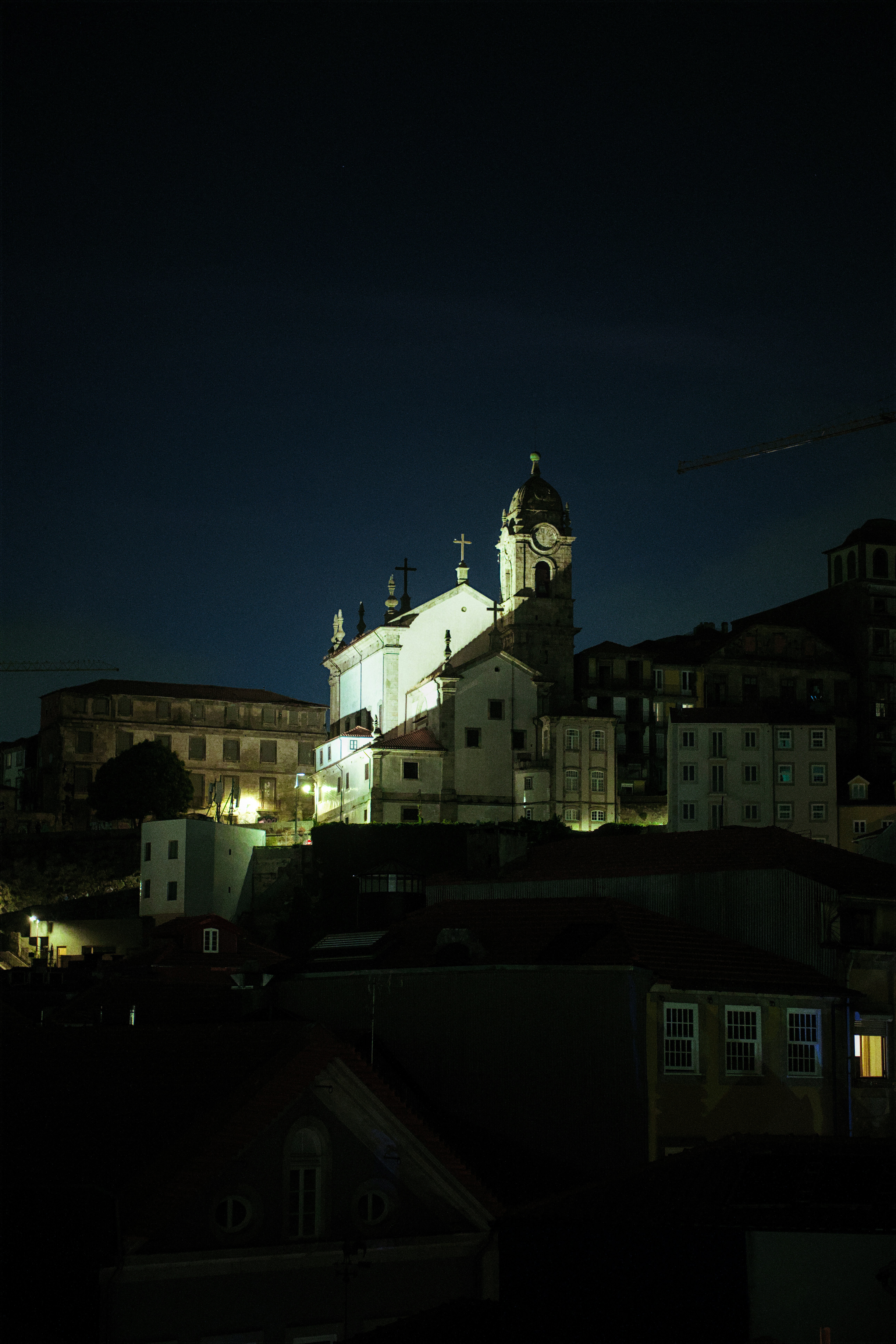 Church illuminated at night with city buildings.