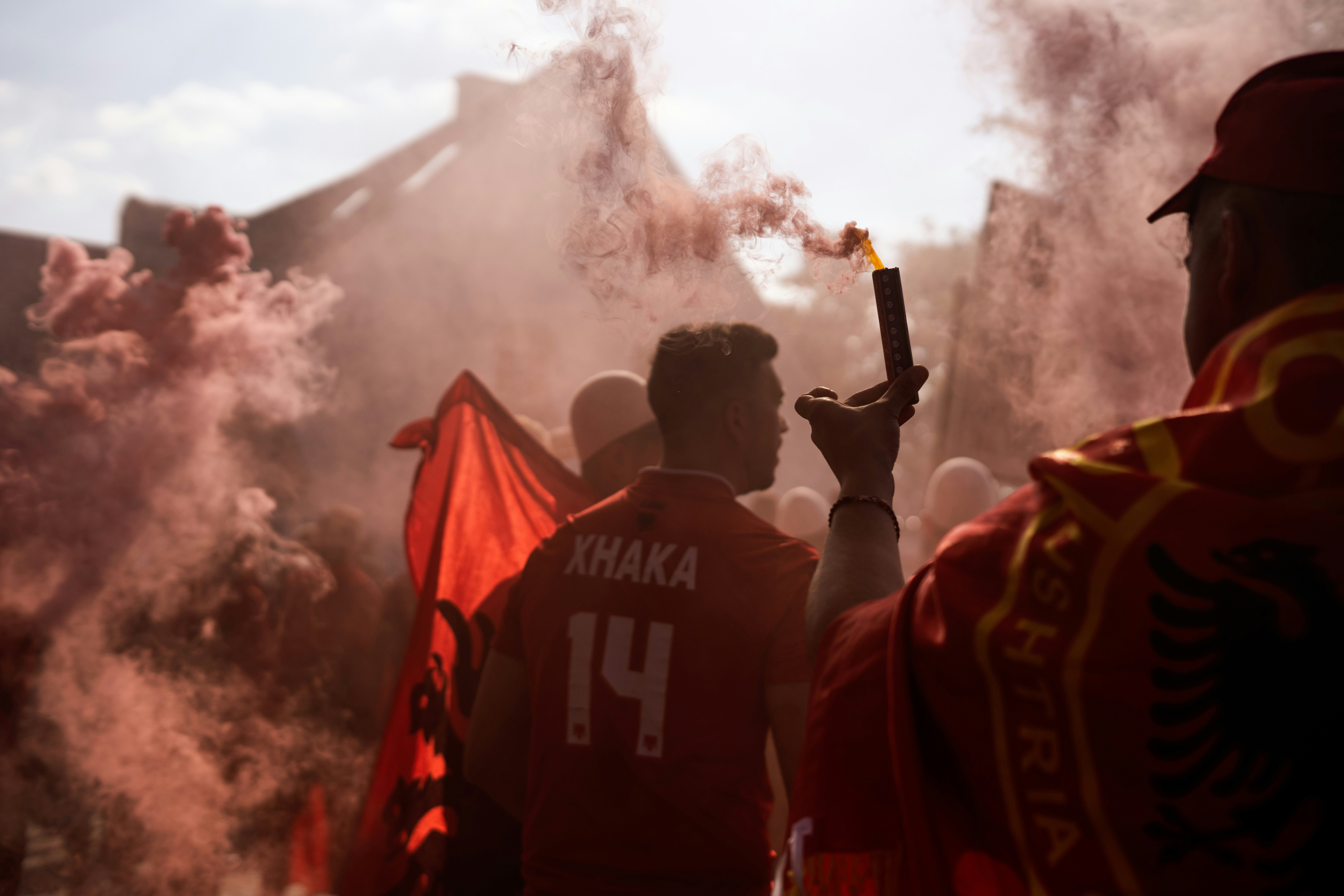 Fans rally with vibrant smoke flares and flags, showcasing their team spirit during a lively event.