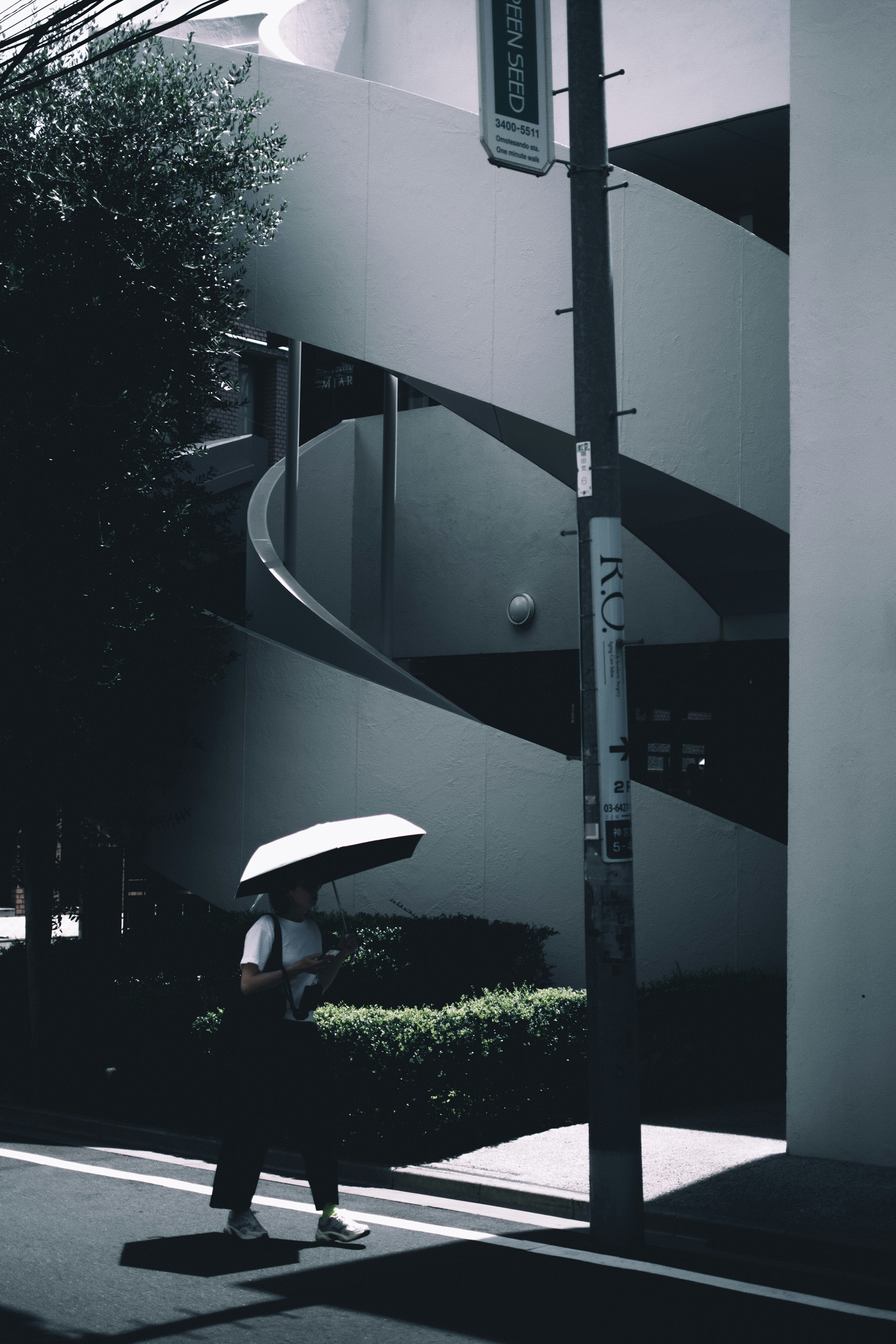 Person with umbrella walks on street near building