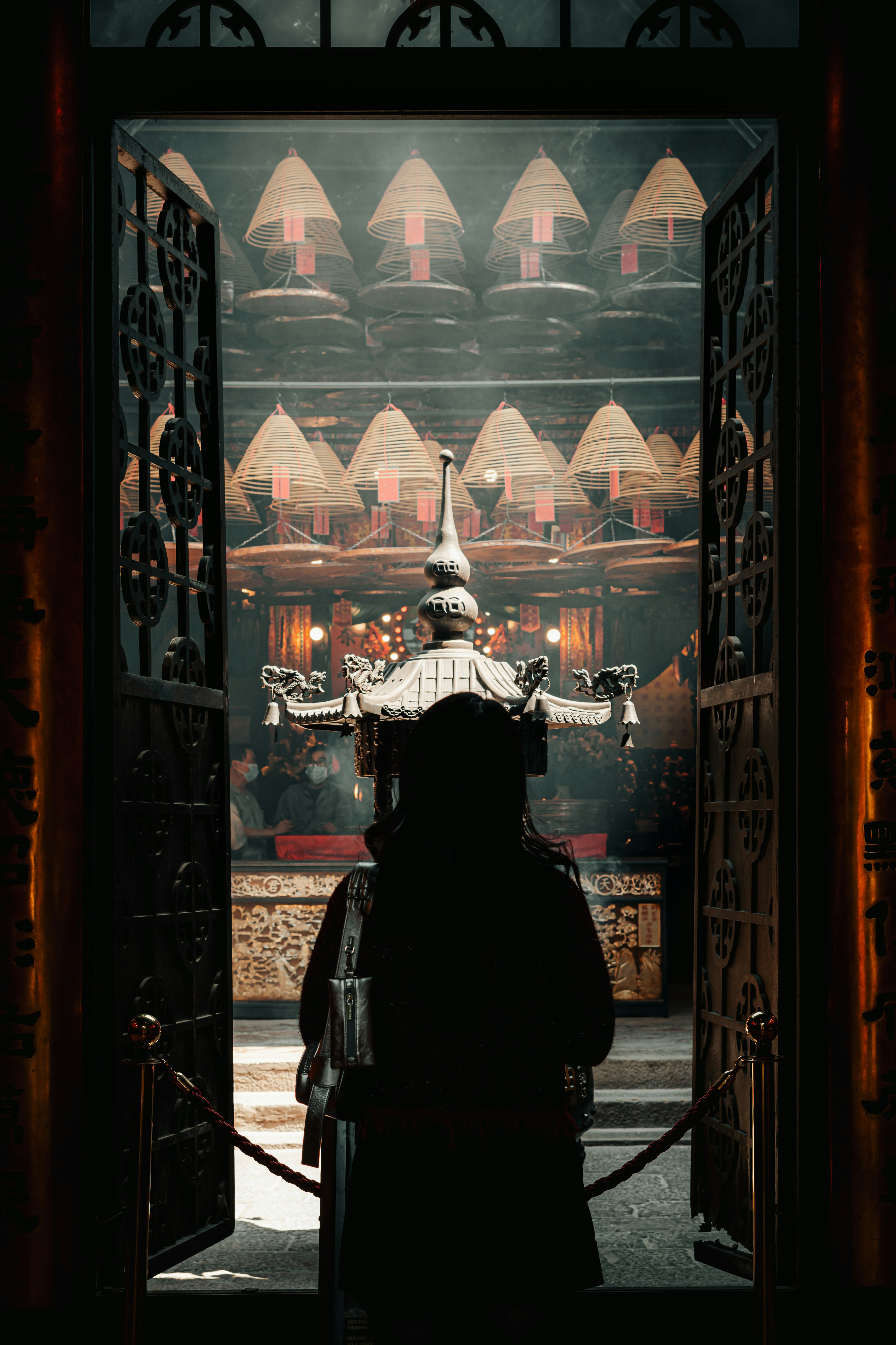 Hong Kong Street View - Sun Hung | Silhouette of person entering ornate temple with incense burners.