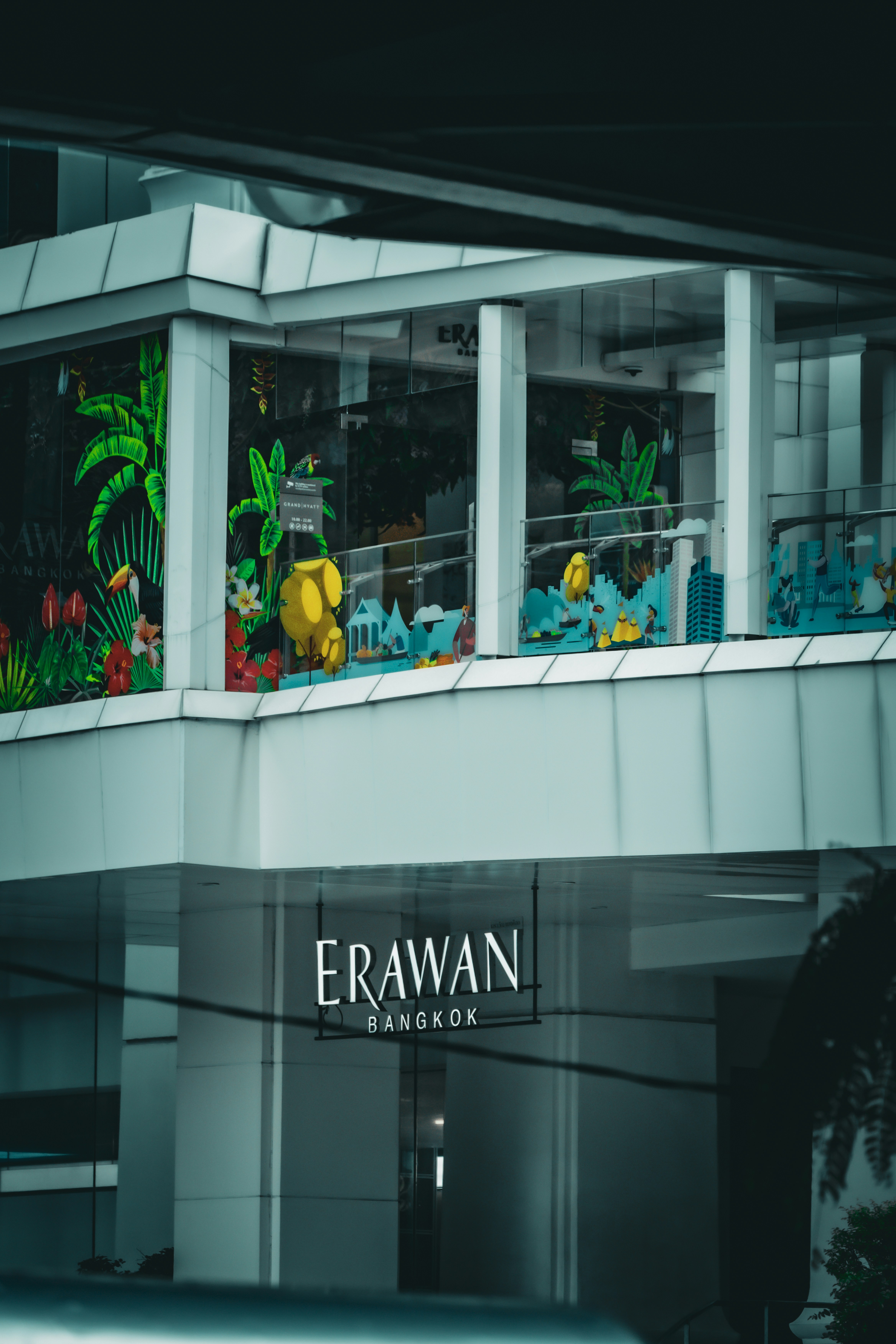 Colorful decorations adorn the Erawan Bangkok's exterior, showcasing a lively blend of nature and urban life. The scene captures the essence of modern city aesthetics.