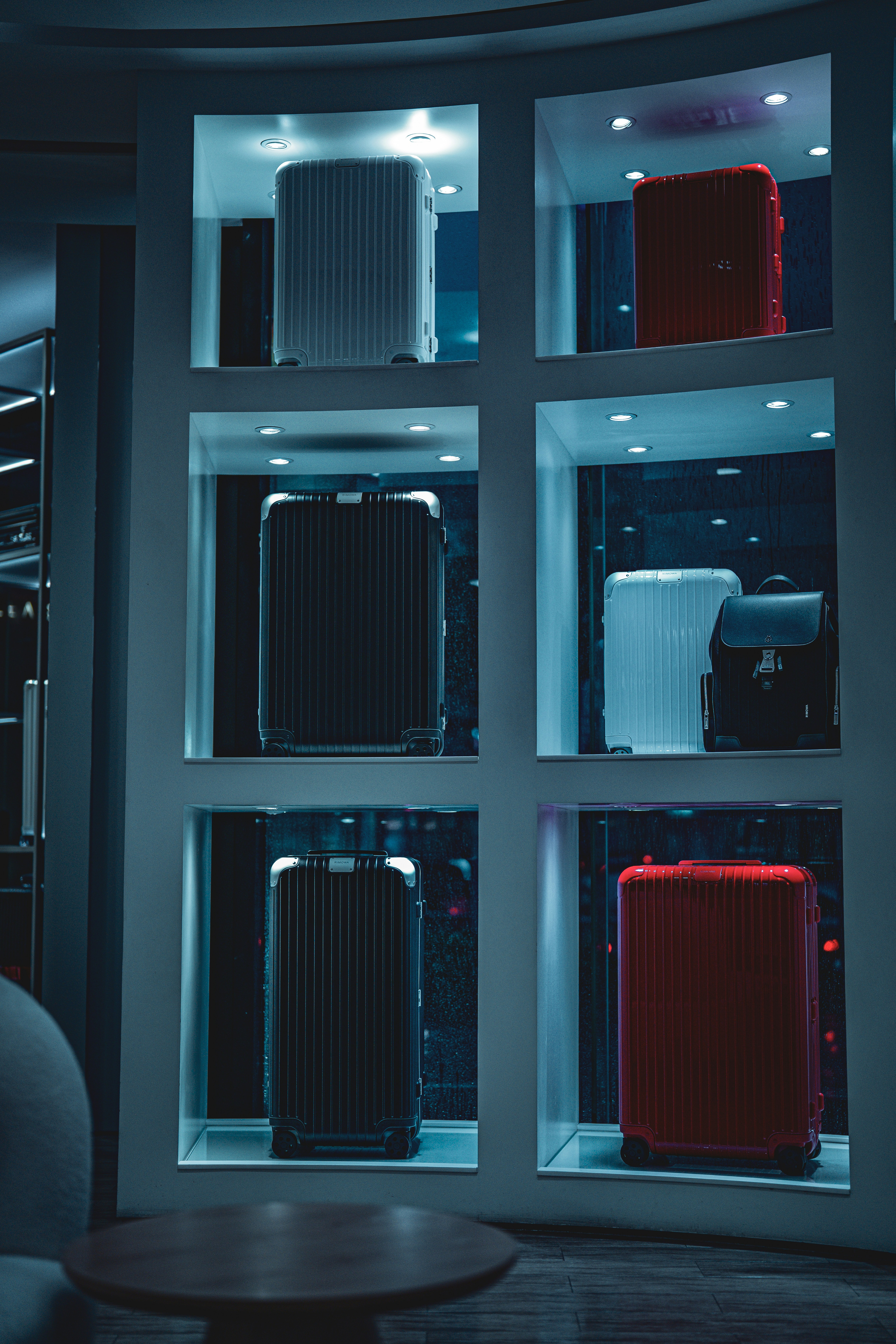 A stylish showcase featuring an array of colorful suitcases and a bag, illuminated by soft LED lights in a contemporary display case.