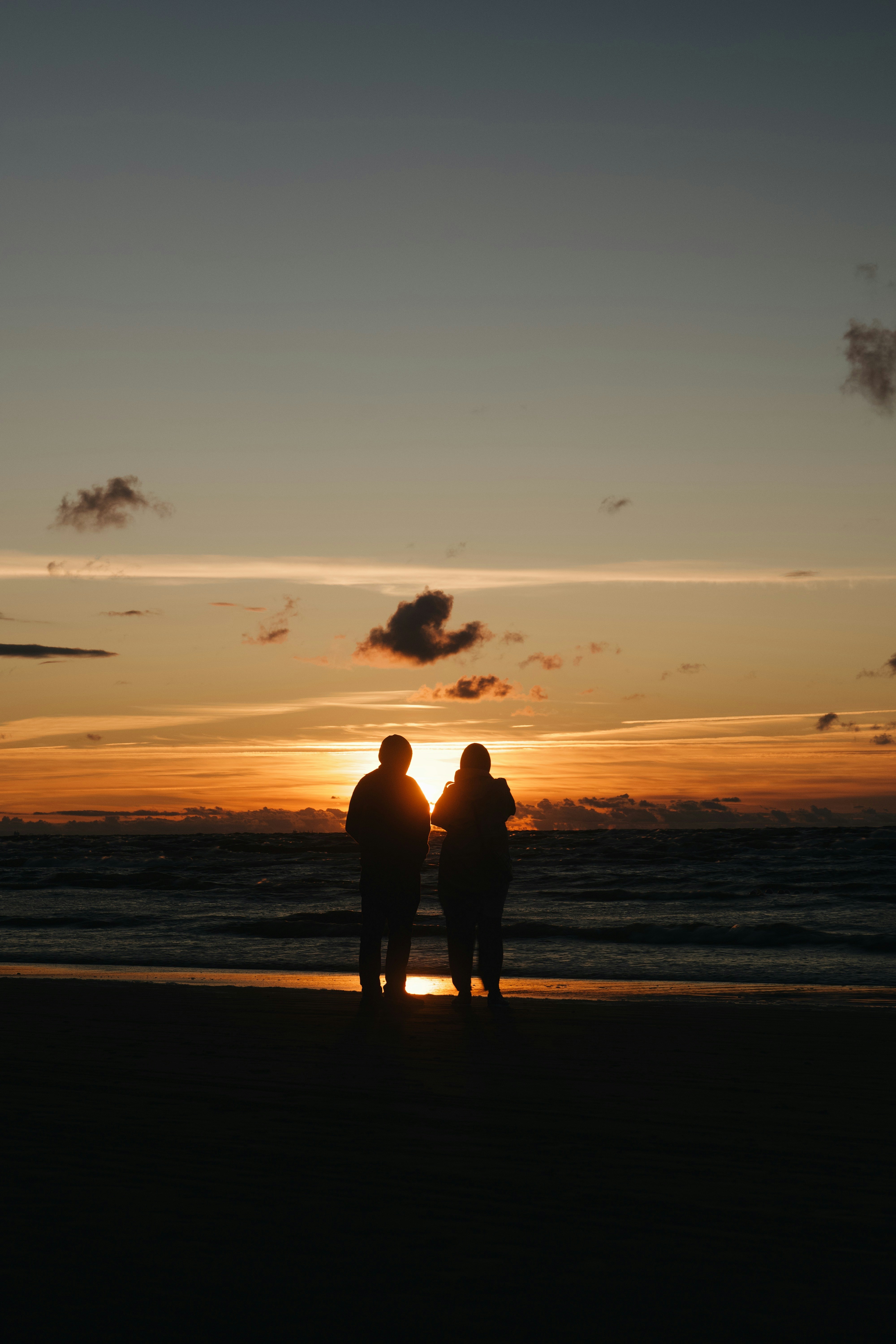 Two people watch a sunset over the ocean photo – Free Beach Image on ...