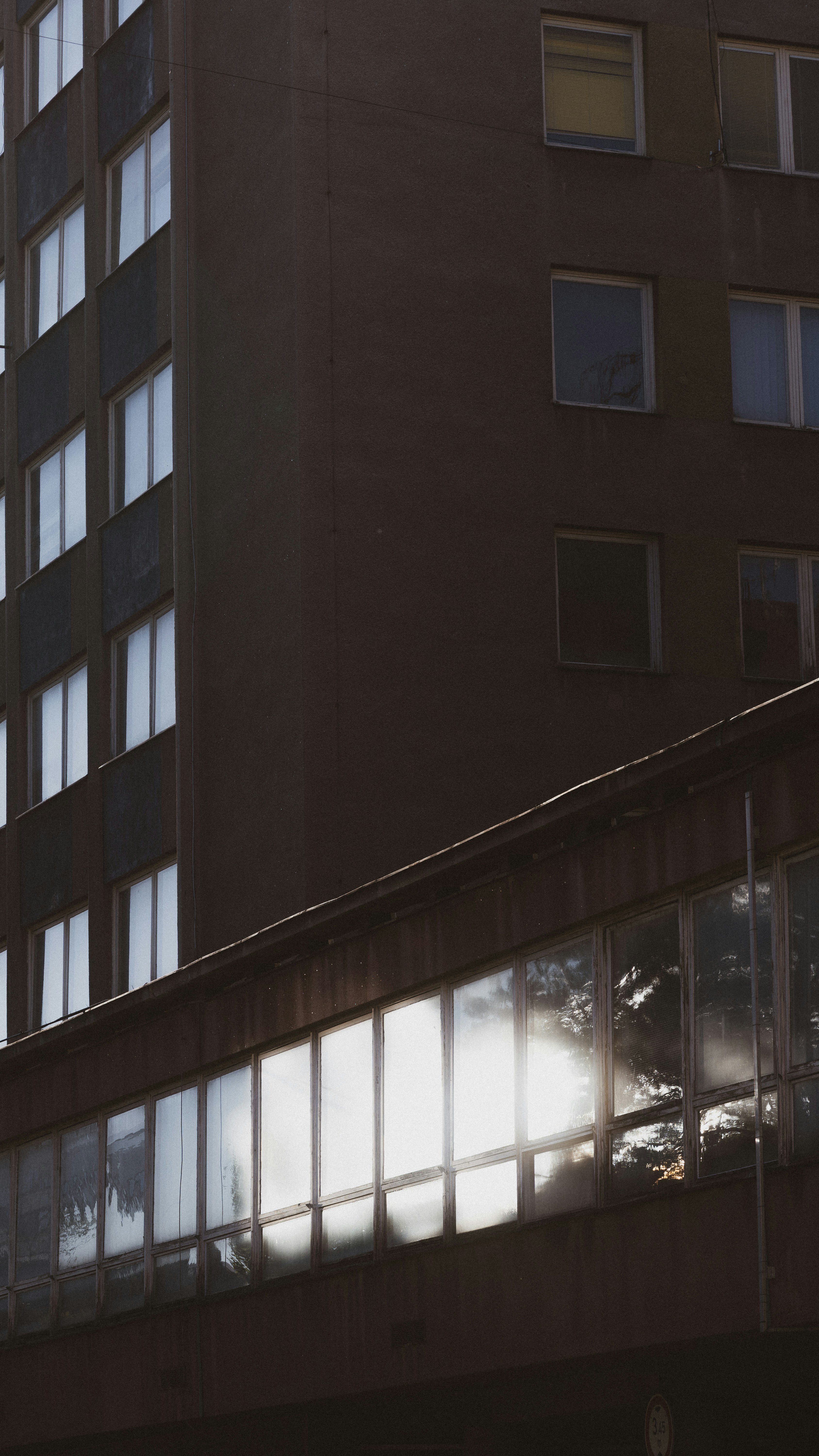 Photo of a vintage building reflecting sunlight | Sunlight streams through a glass walkway between buildings.