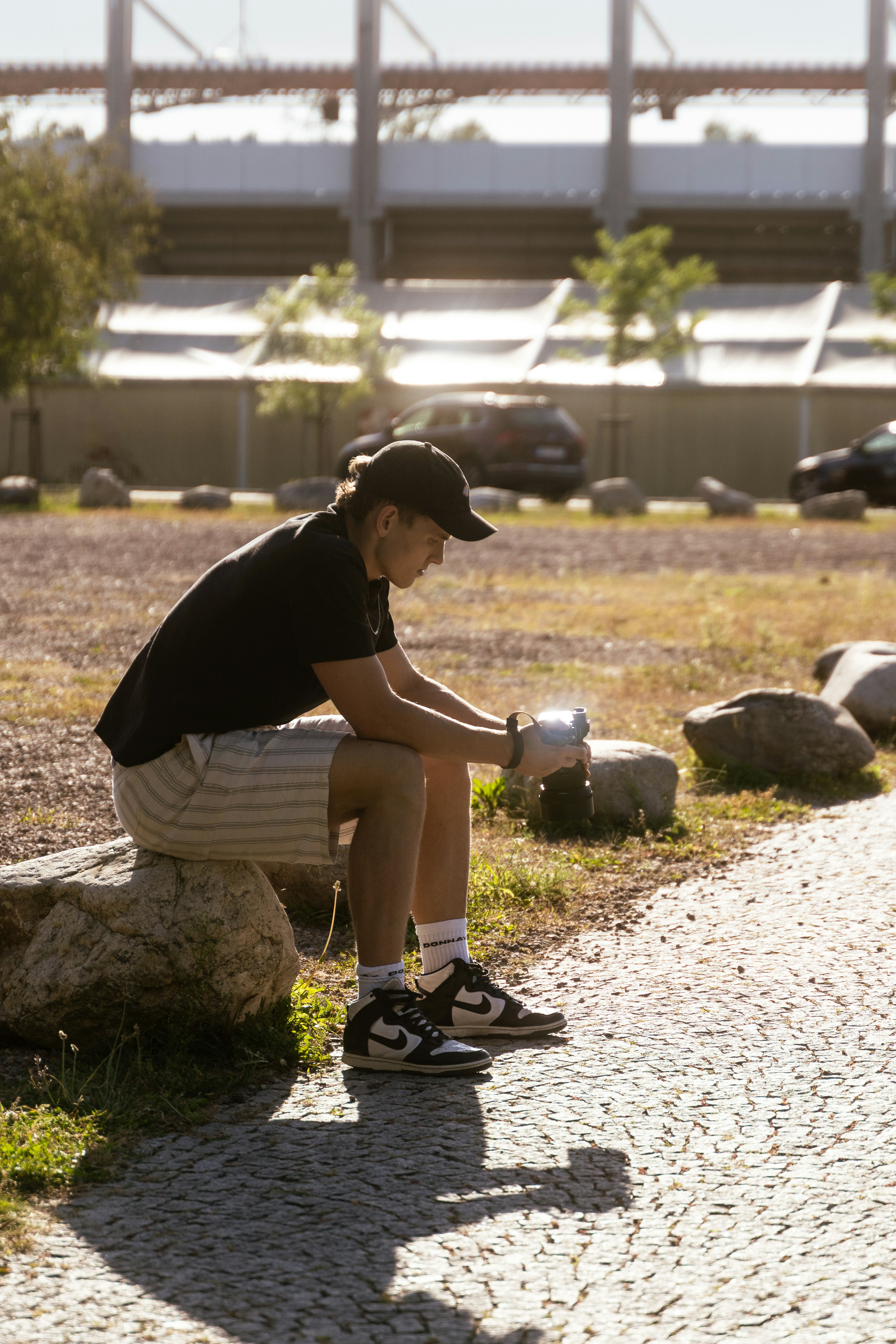 Sunlight is reflecting in man's sony camera | Person sitting outdoors holding a can