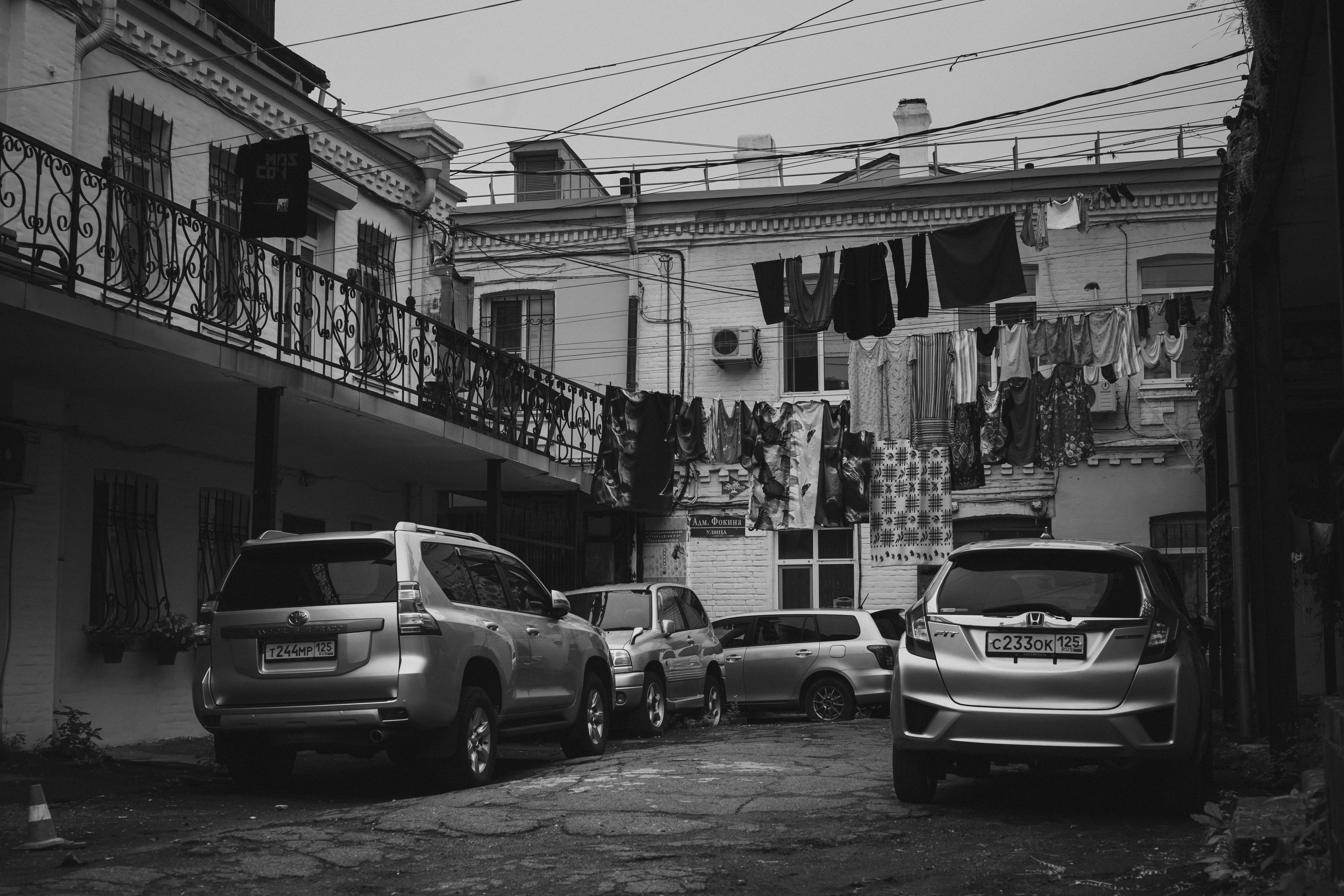 Monochrome Courtyard: Laundry Lines, Cars, and a Narrow Alley