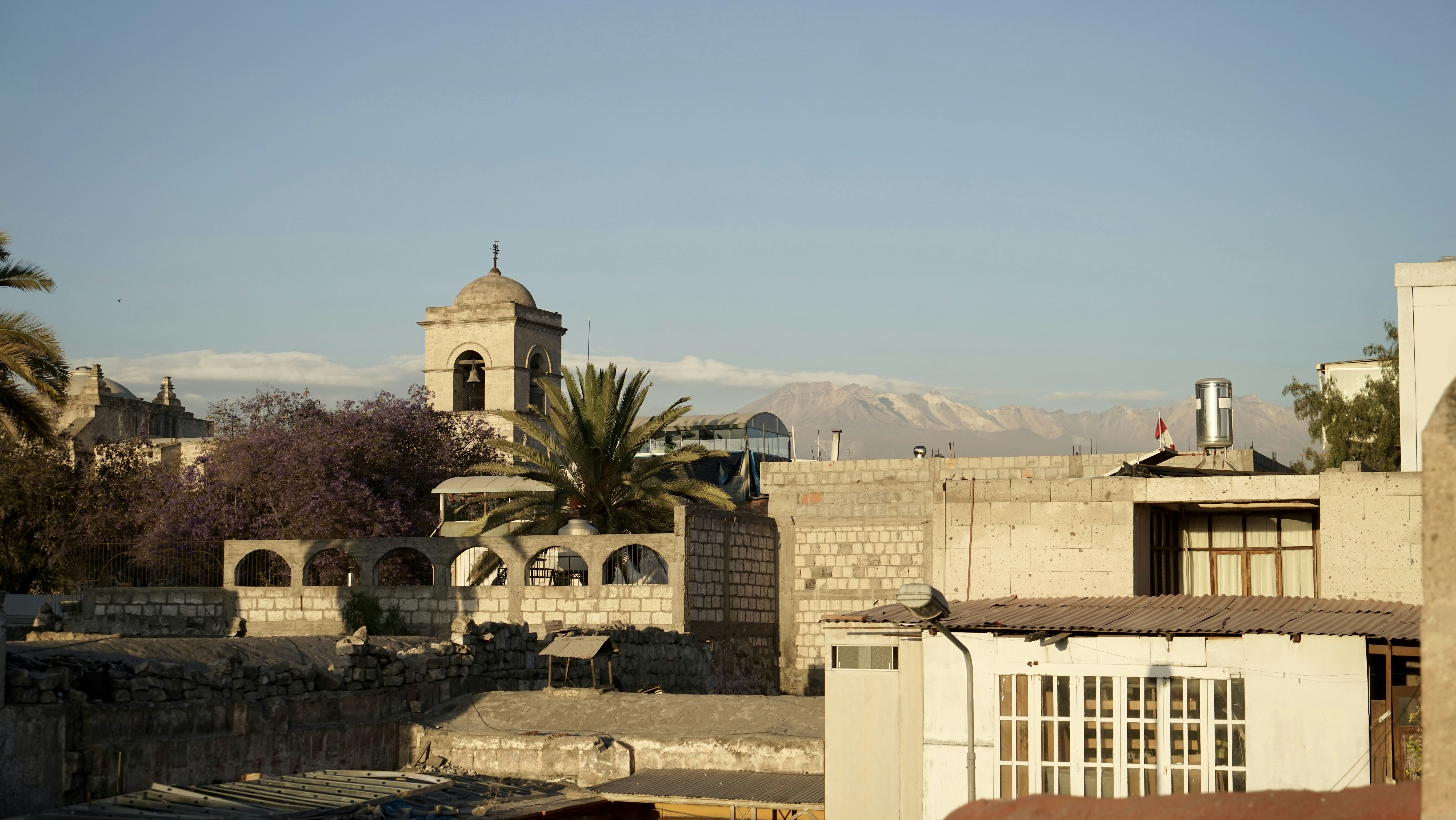 Buildings with a church steeple against distant mountains.