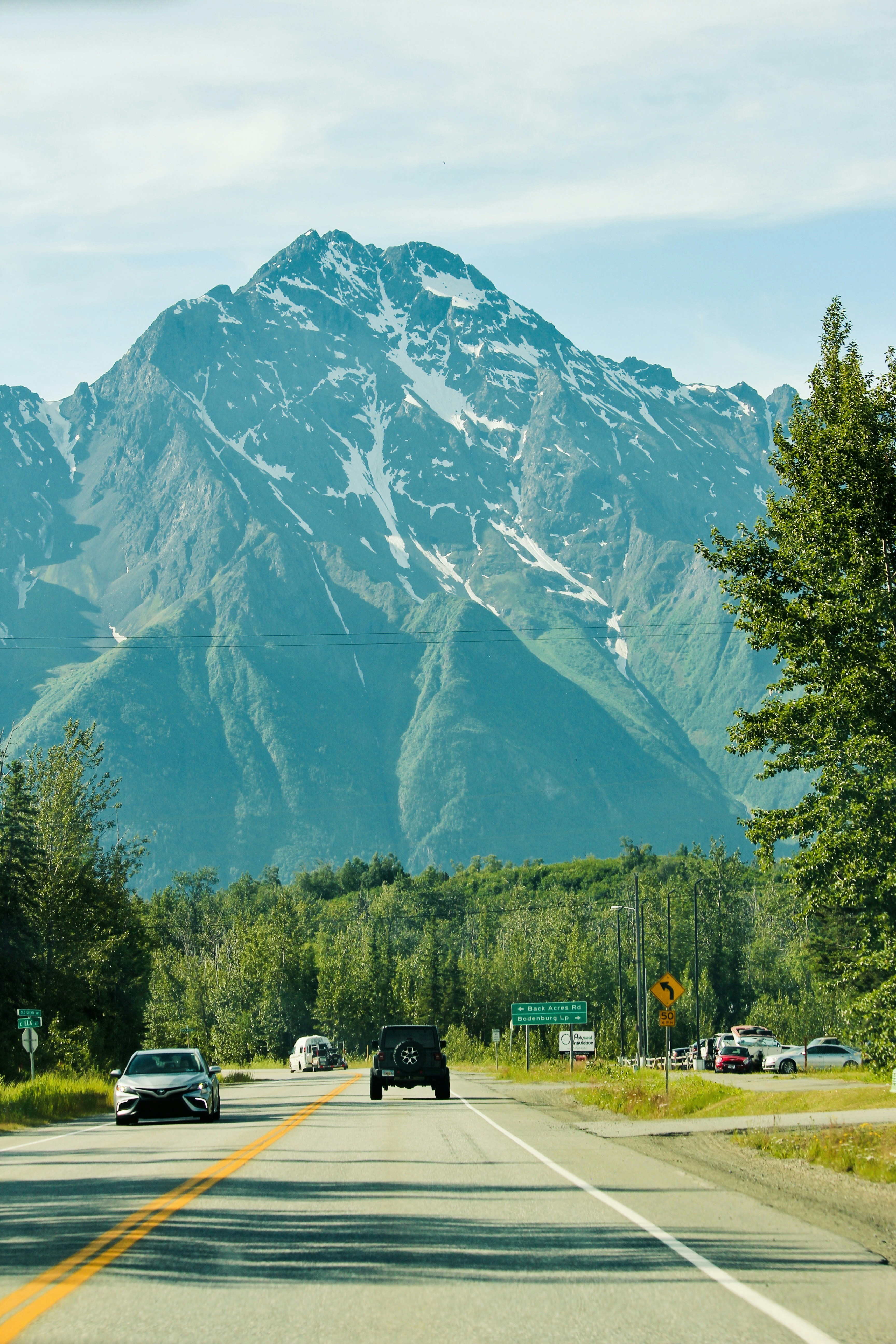 Mt. Pioneer | Cars drive on a road towards a snow-capped mountain.