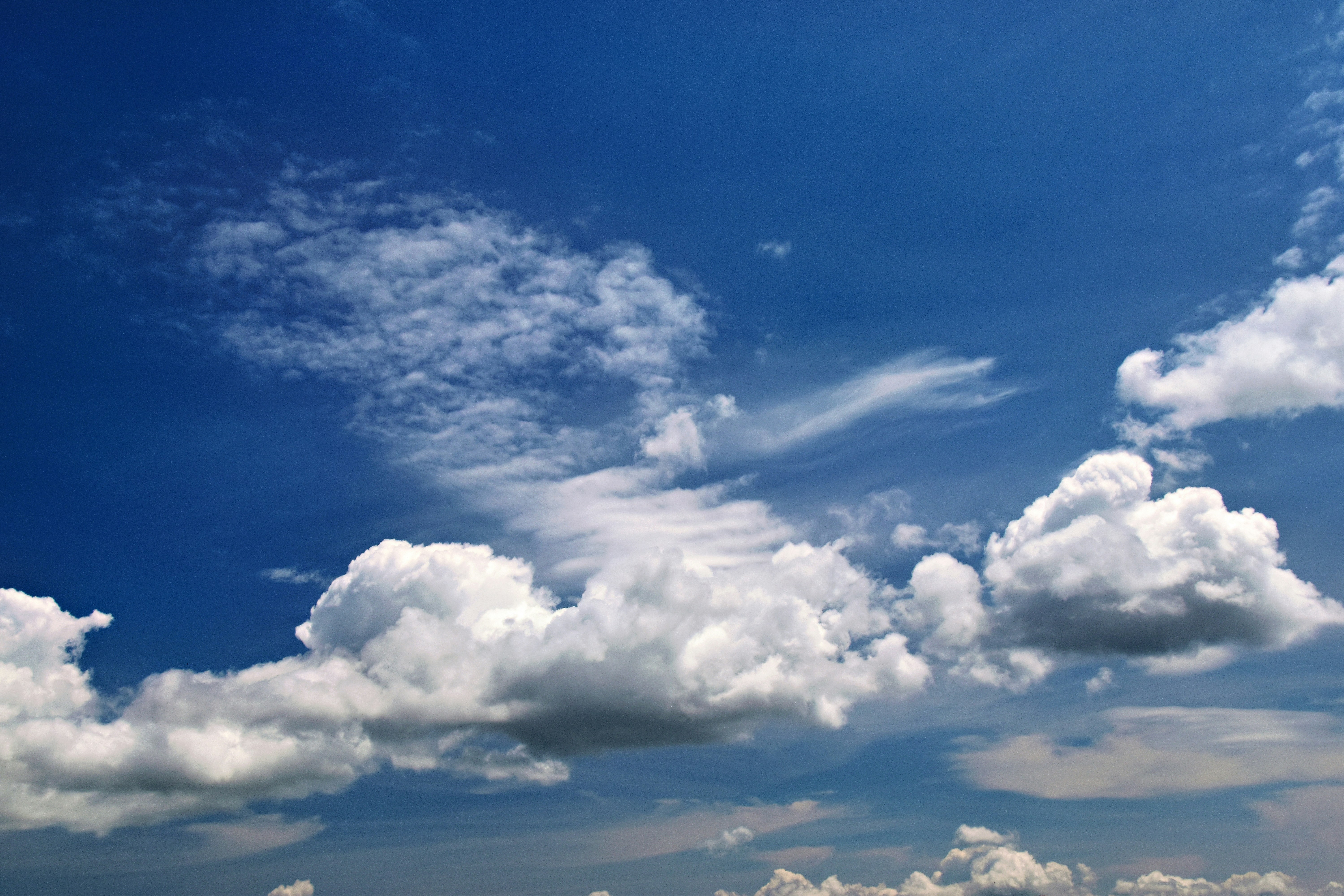 Fluffy white clouds drift across a bright blue sky