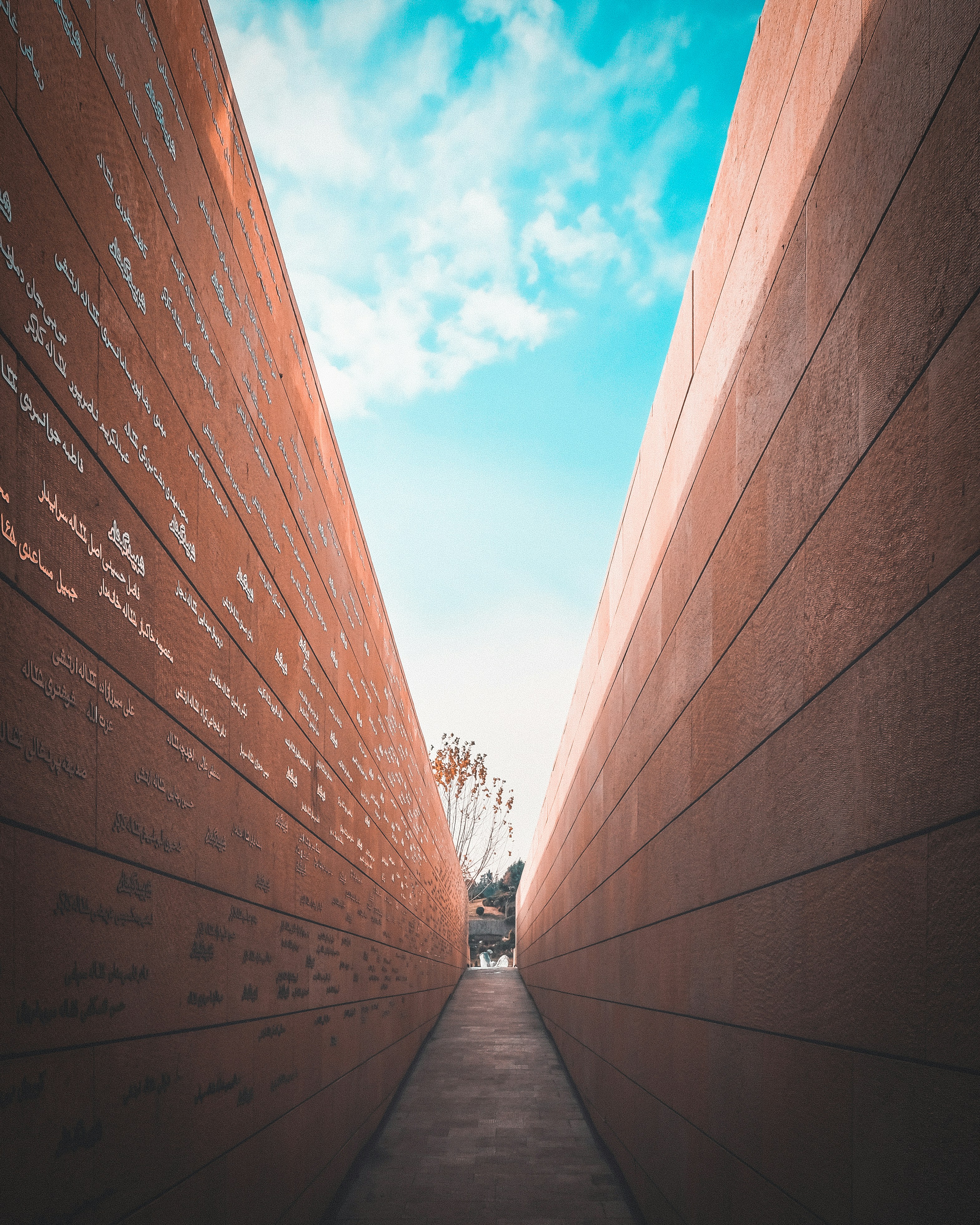 Sam Moghadam – Artistic, Architectural & Industrial Photographer Professional photographer blending creativity with precision. Specialized in art, architecture, and industrial photography, with expertise in portrait and advertising work. | Tall stone walls leading to a bright sky