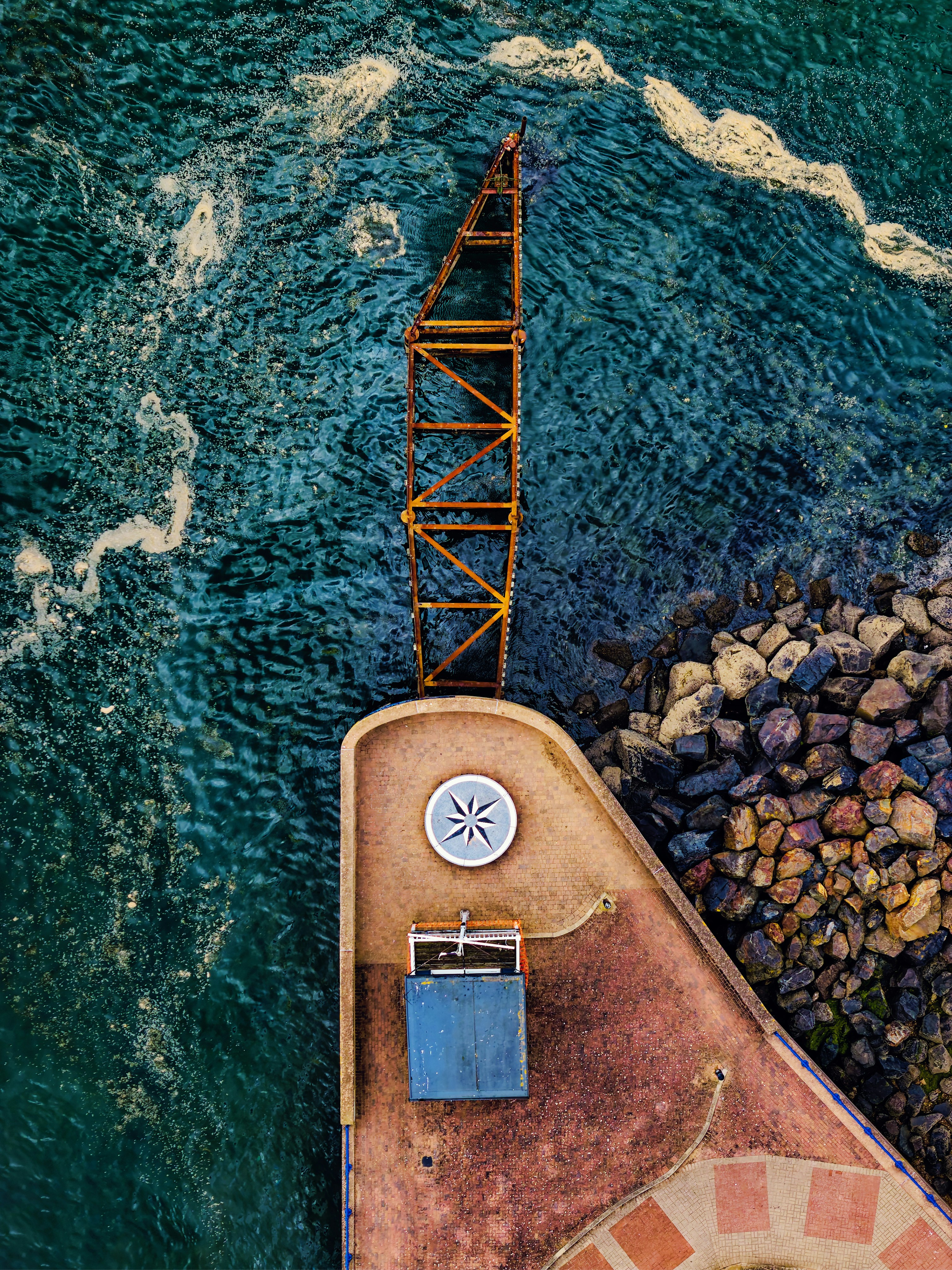All Points South West. Navigation installation, Exmouth Marina, Devon, UK | Rusty metal structure over textured blue water