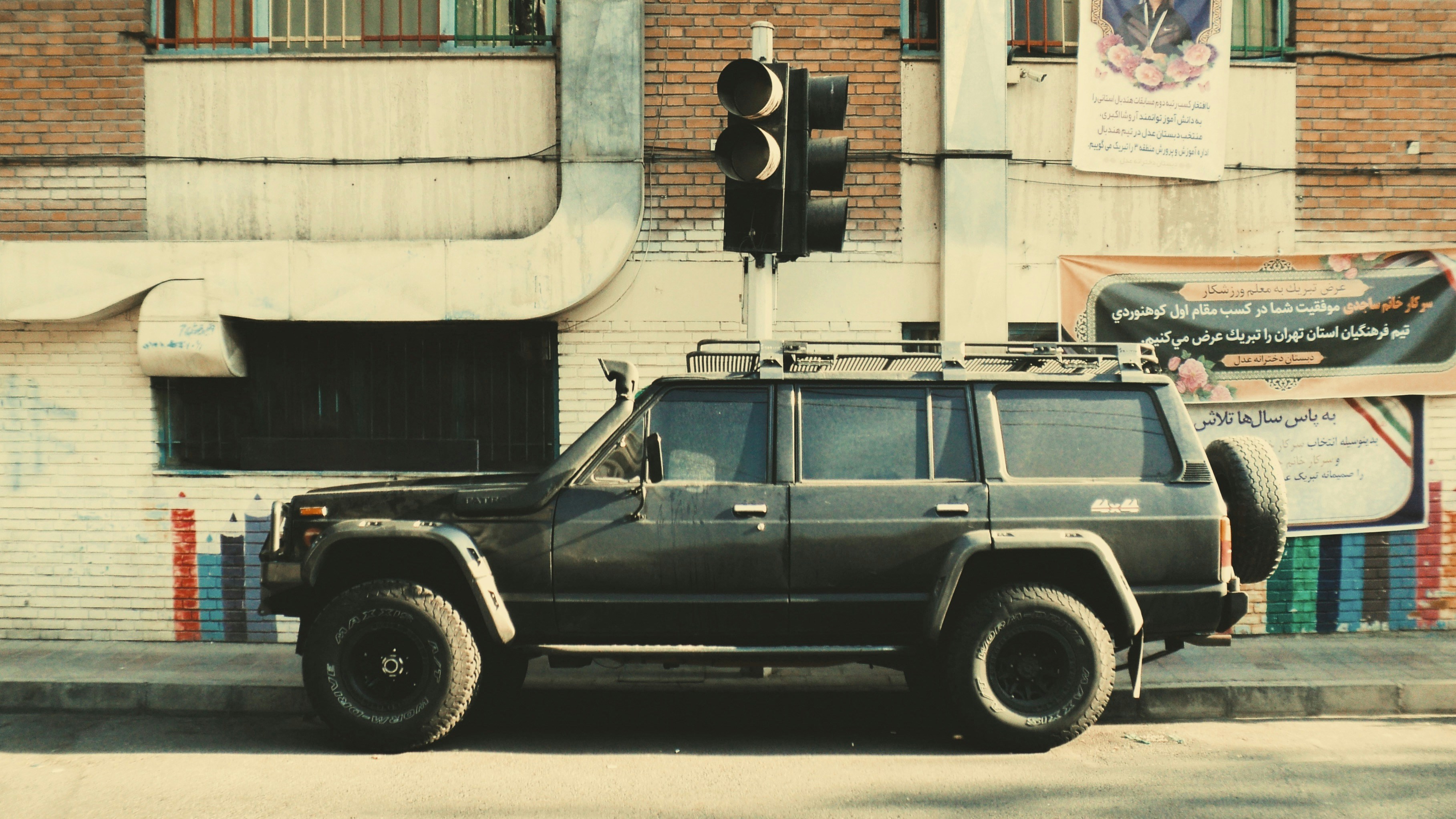 An urban explorer, ready for the open road. | Dark suv parked near a traffic light.