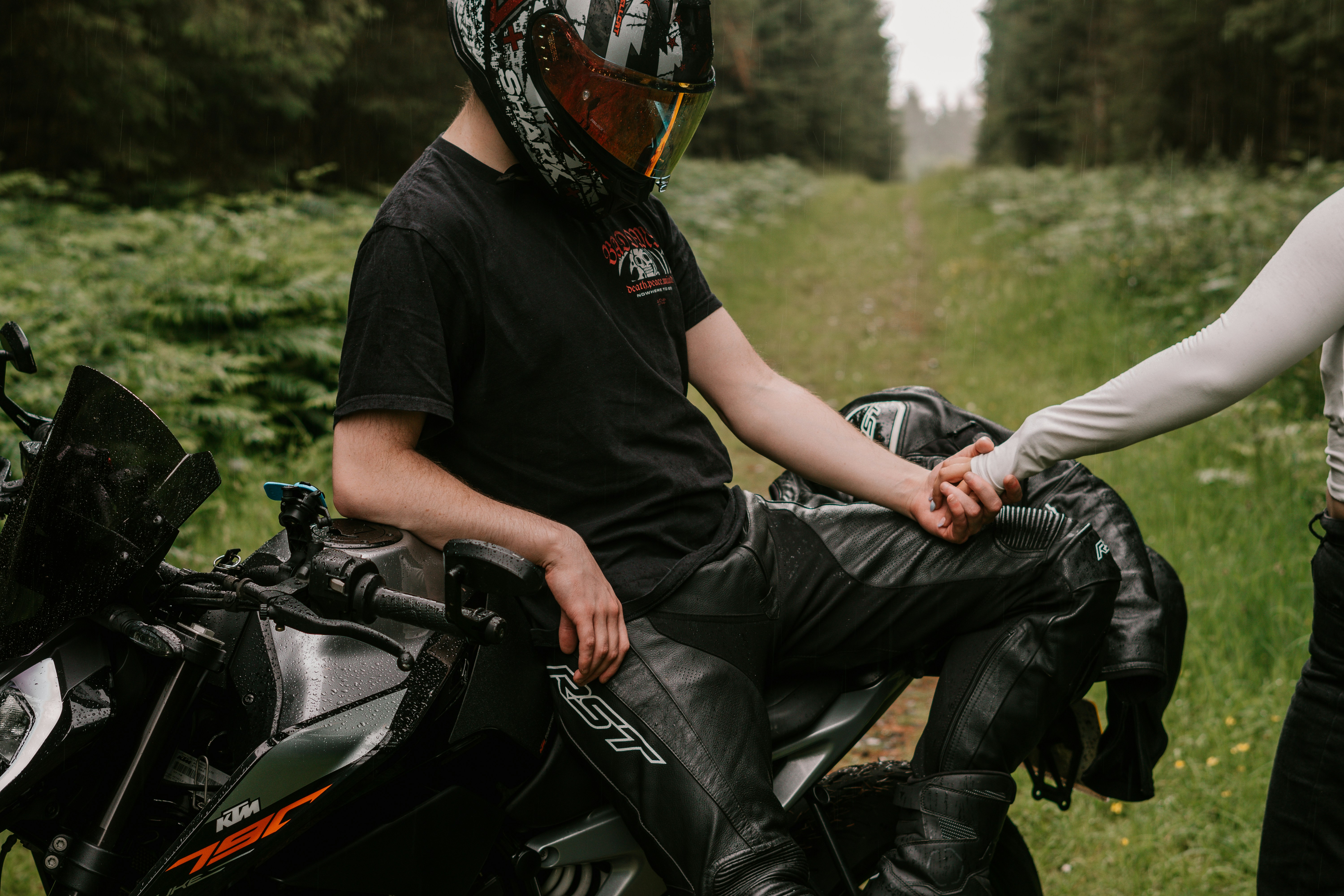 Couple holding hands by motorcycle in forest