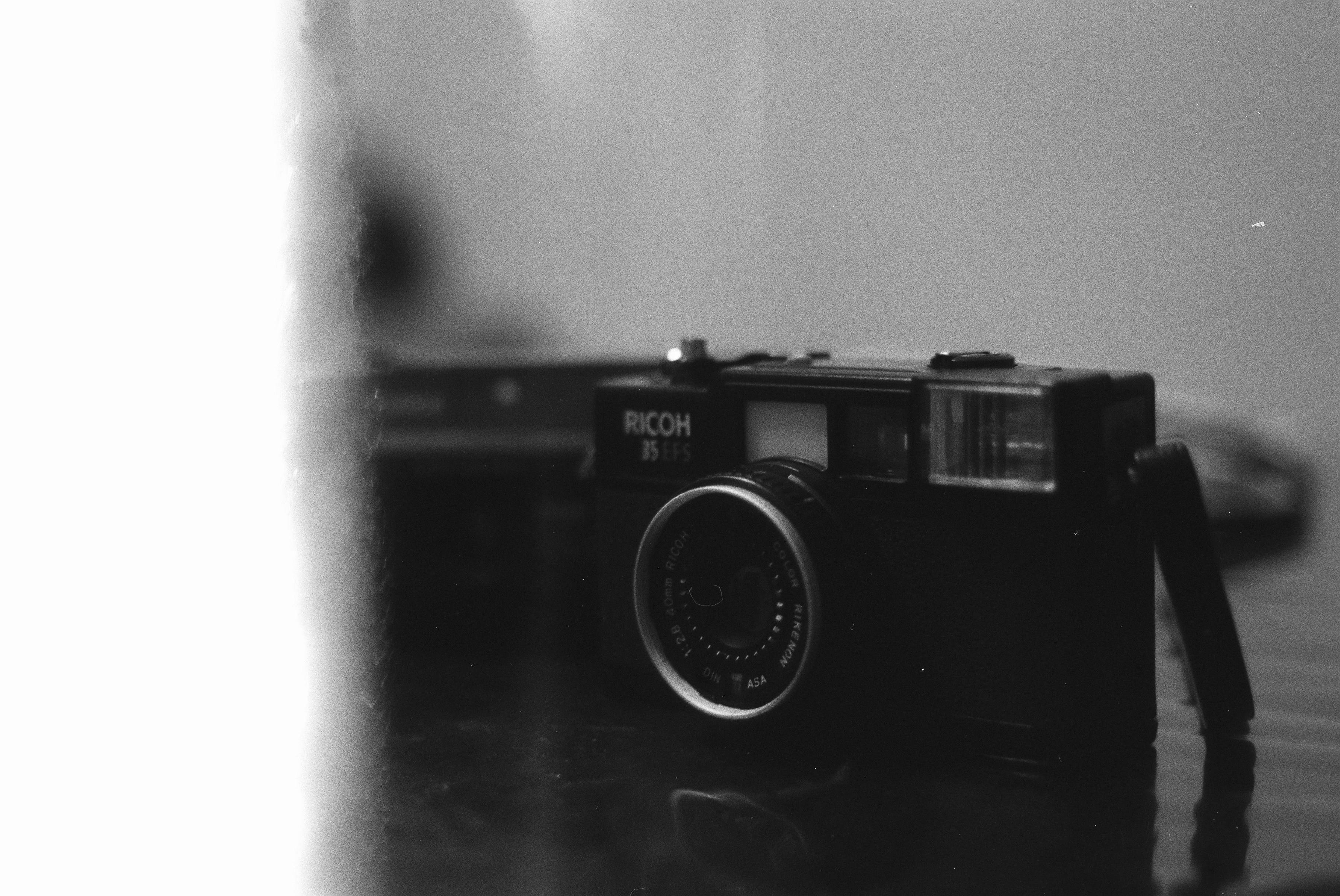 Black ricoh camera with strap on table