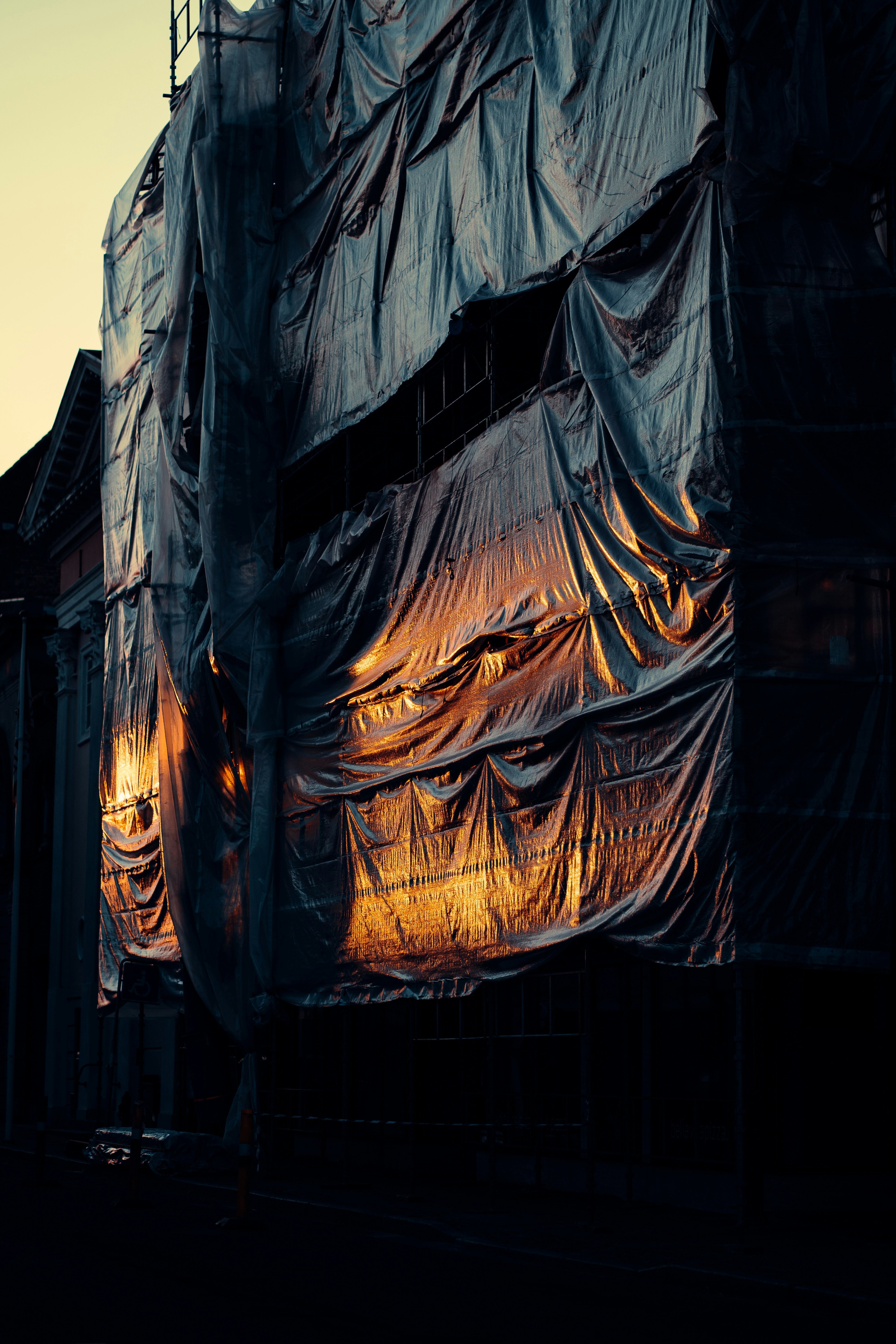 Building covered in tarpaulin with sunset reflections
