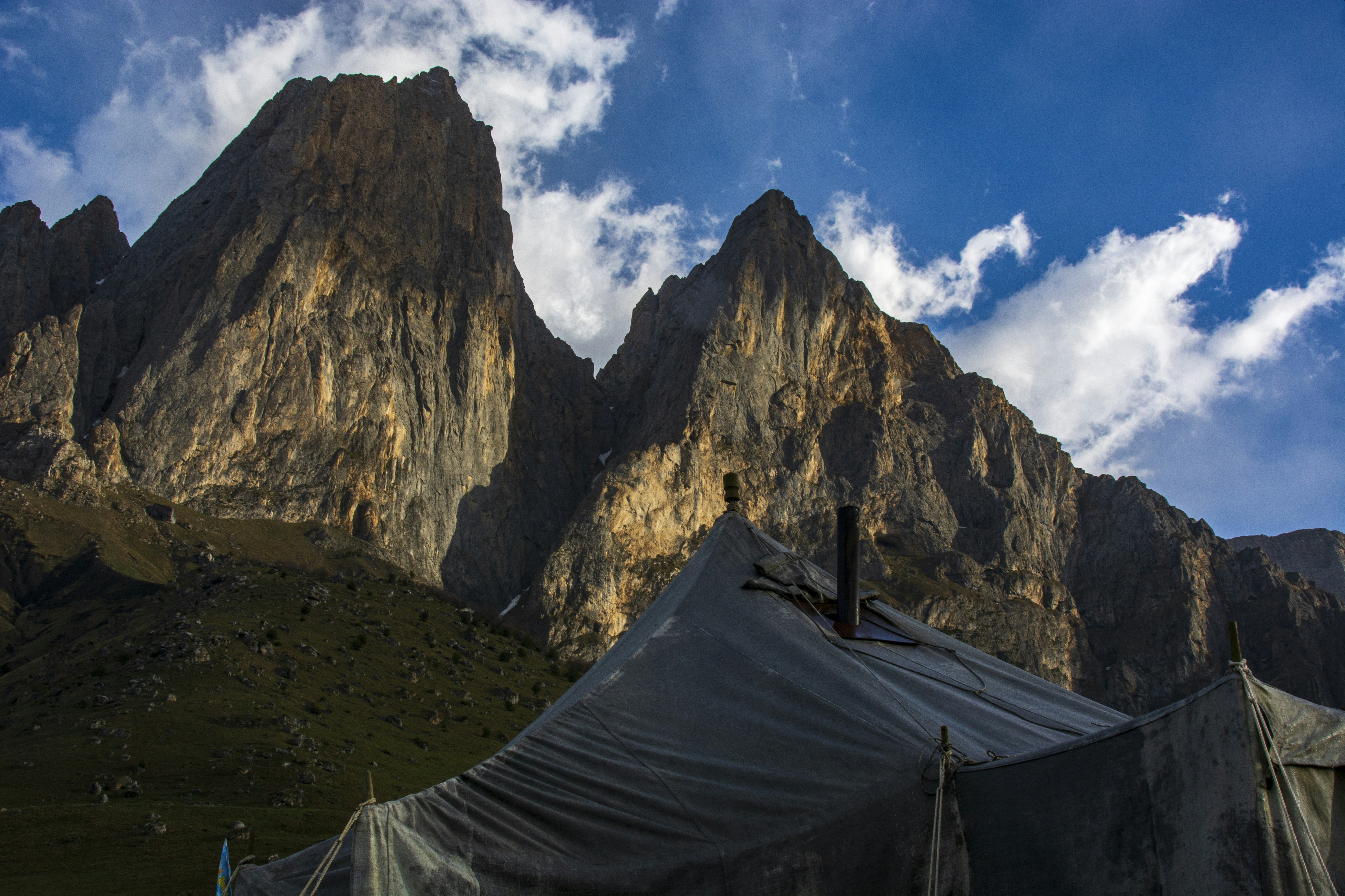 Tent in front of dramatic mountain peaks under a blue sky