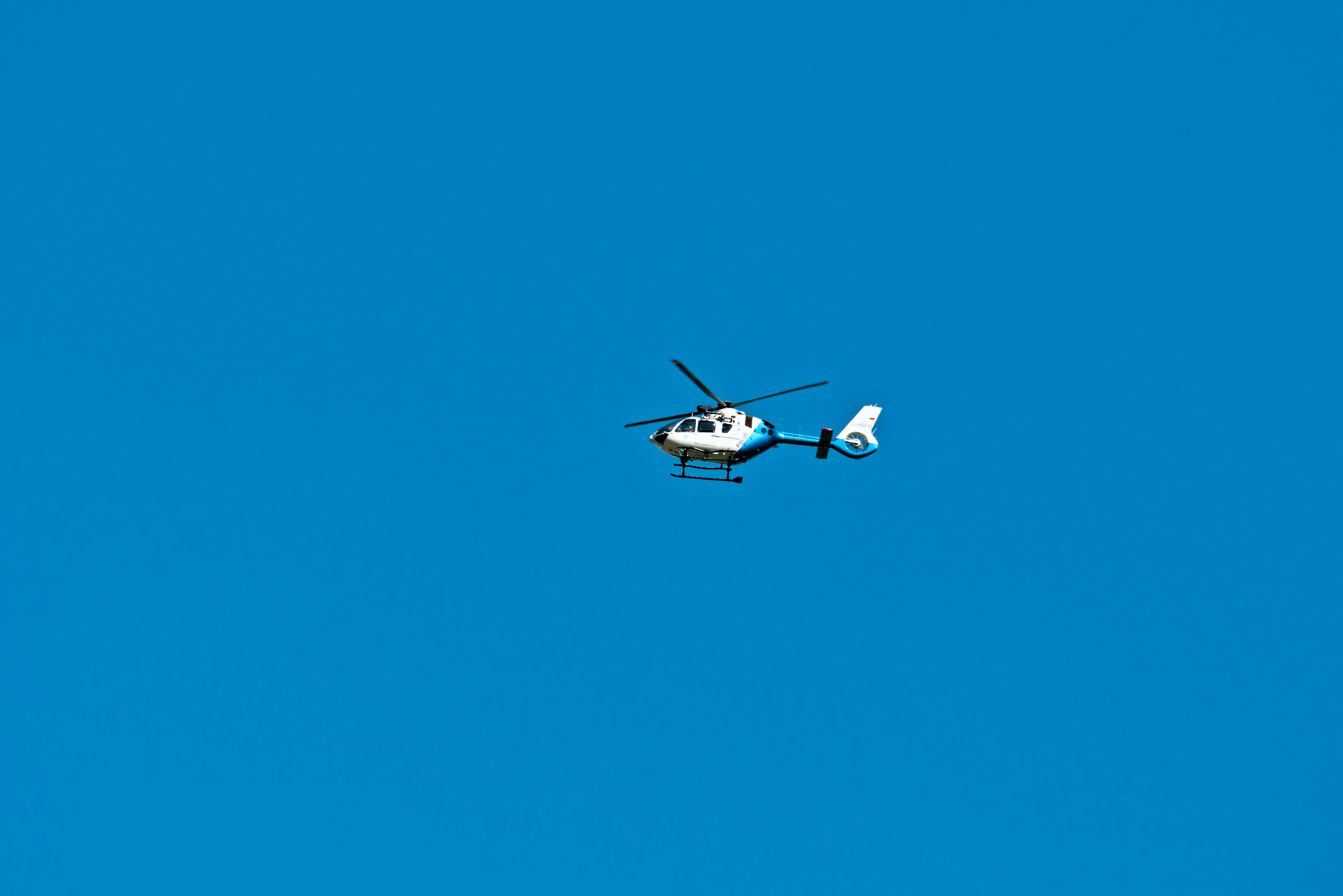 White helicopter flying in clear blue sky