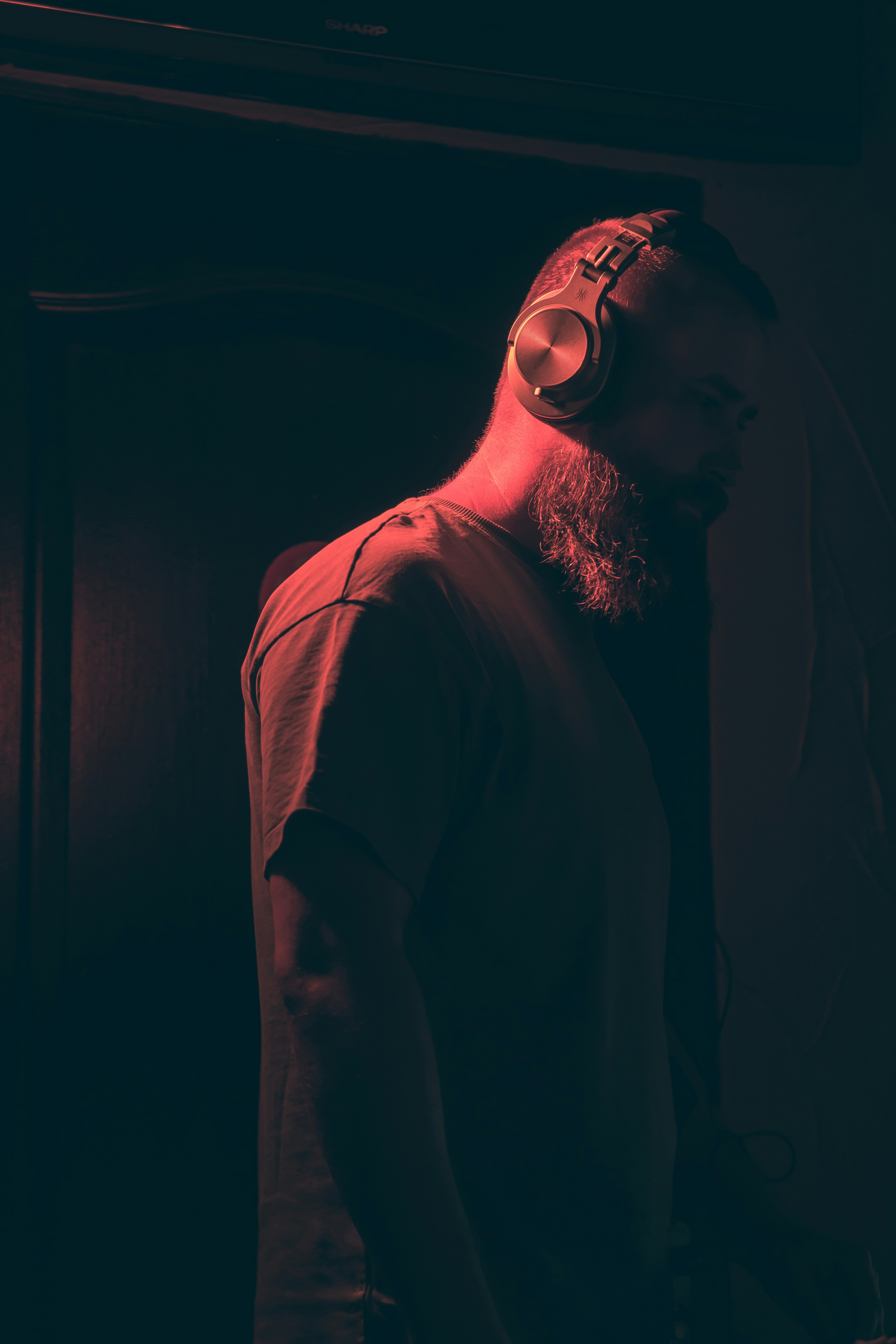 Man with headphones illuminated by red light