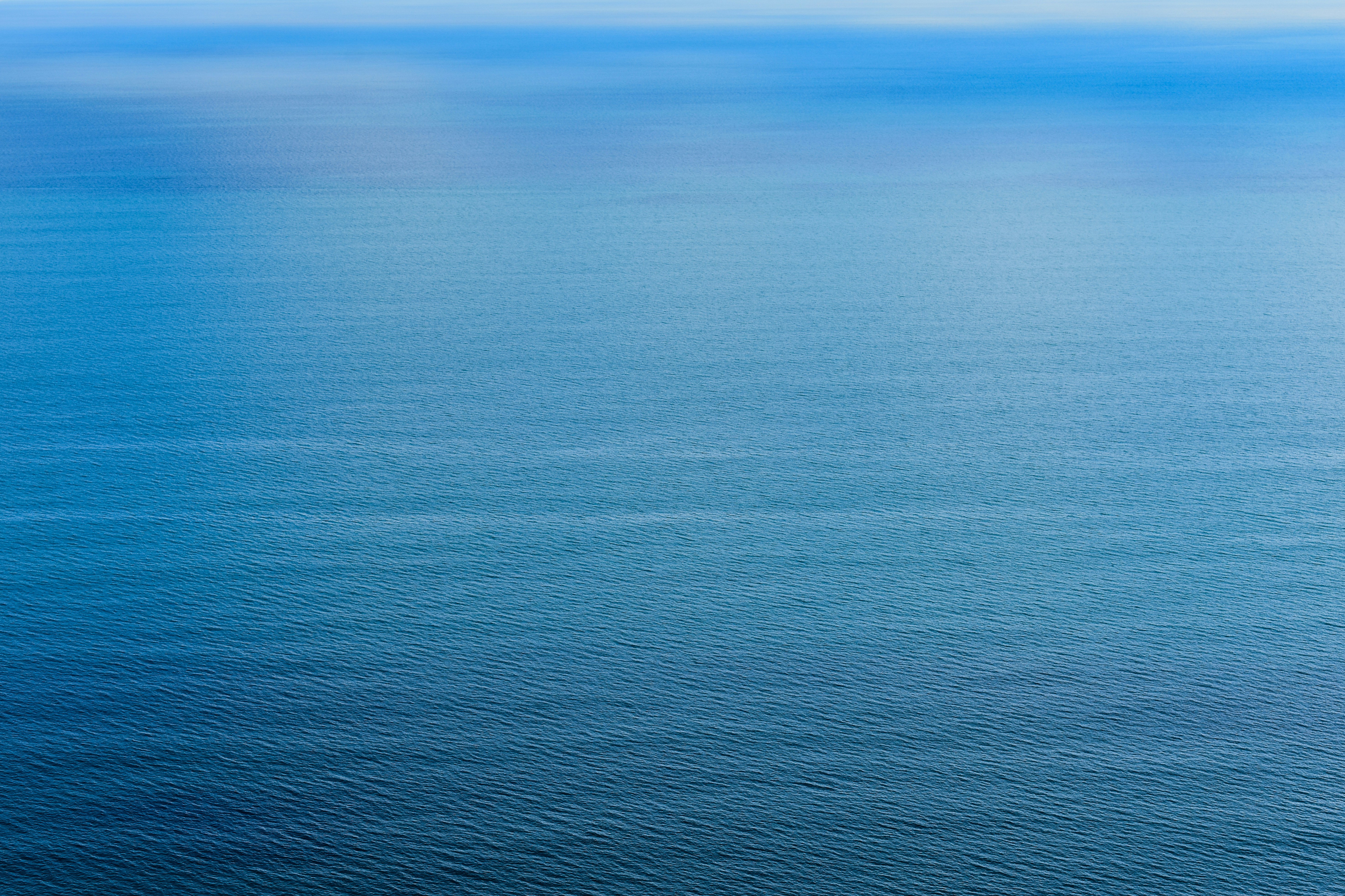 the endlessness of the ocean in an aerial view | Calm blue ocean water with horizon line on horizon