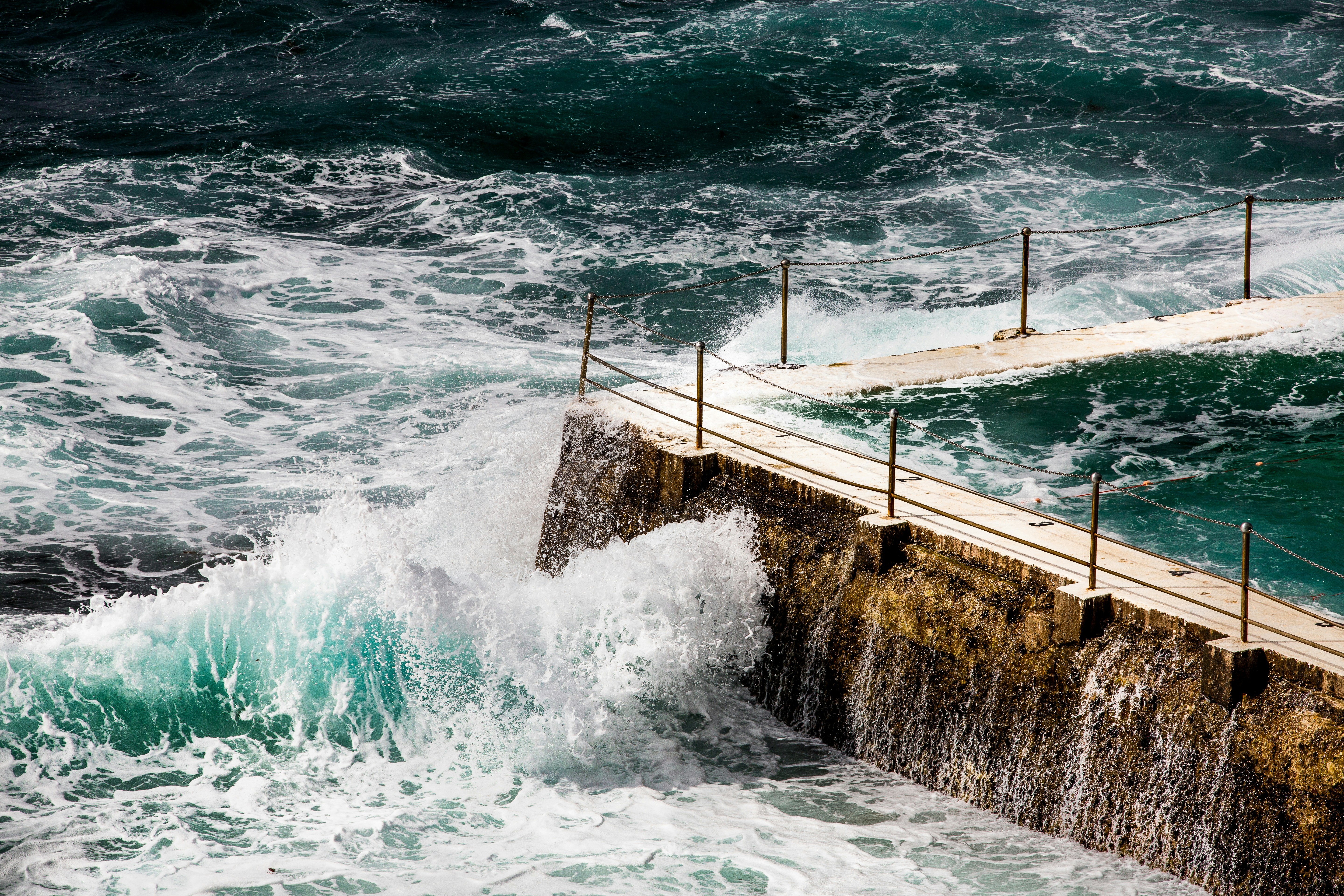 Crashing waves collide with a rocky jetty, creating a dynamic interplay of water and structure. The tumultuous sea showcases nature's raw power.