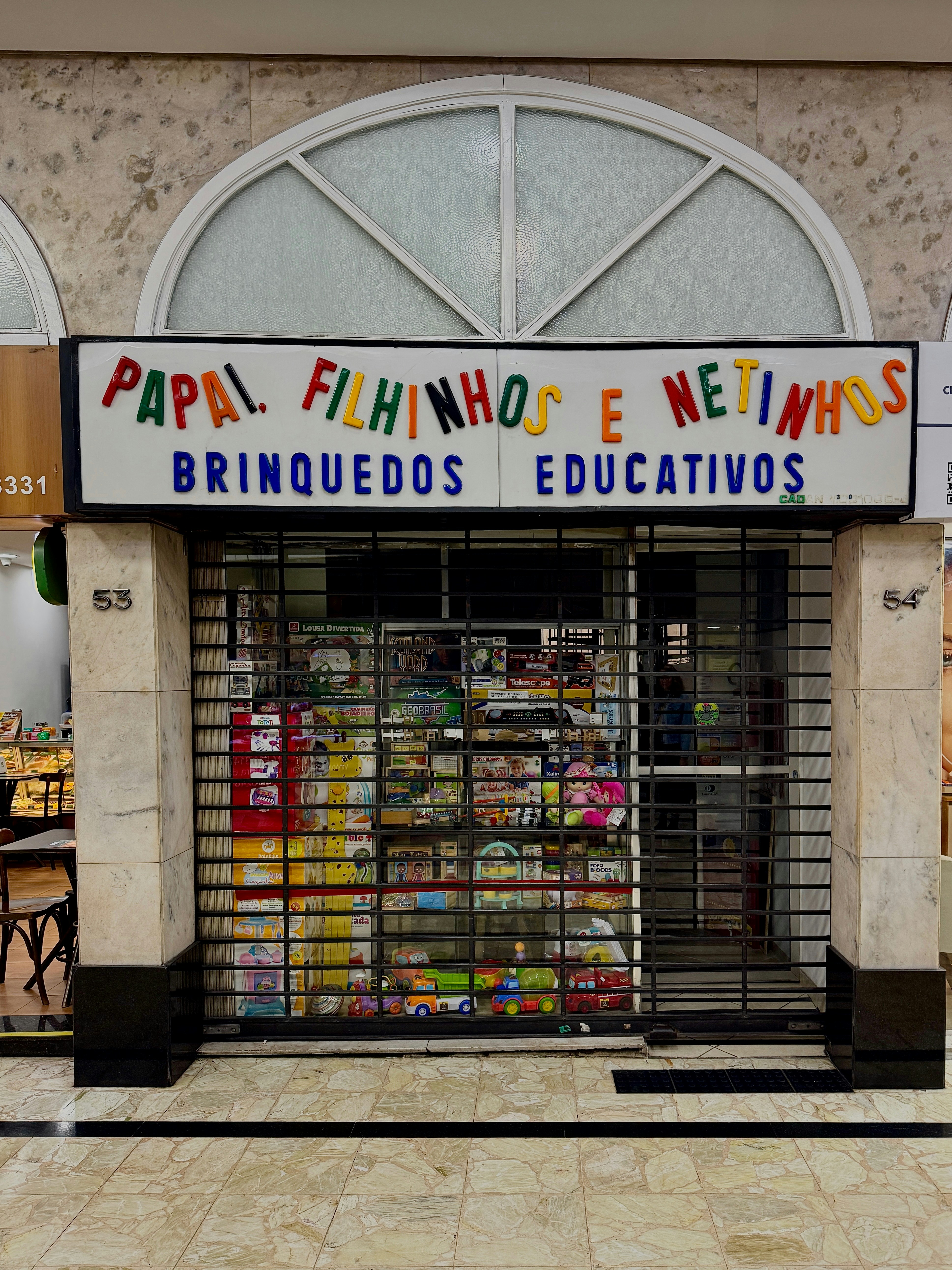Educational toy shop with vibrant signage and a variety of toys displayed behind a metal grate. The shop emphasizes learning through play.