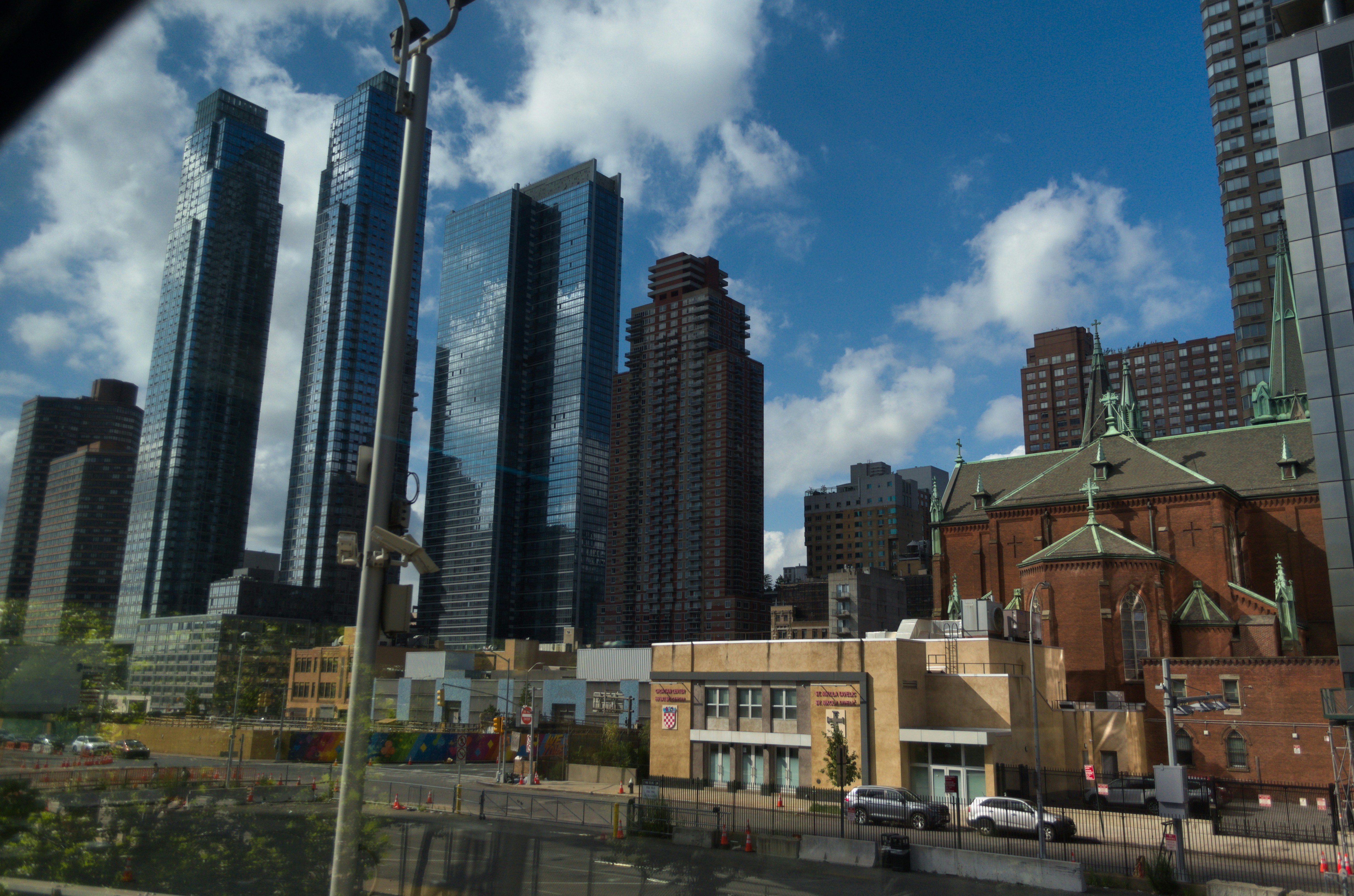 Modern skyscrapers rise behind a historic church, illustrating the blend of architectural eras in a bustling cityscape.