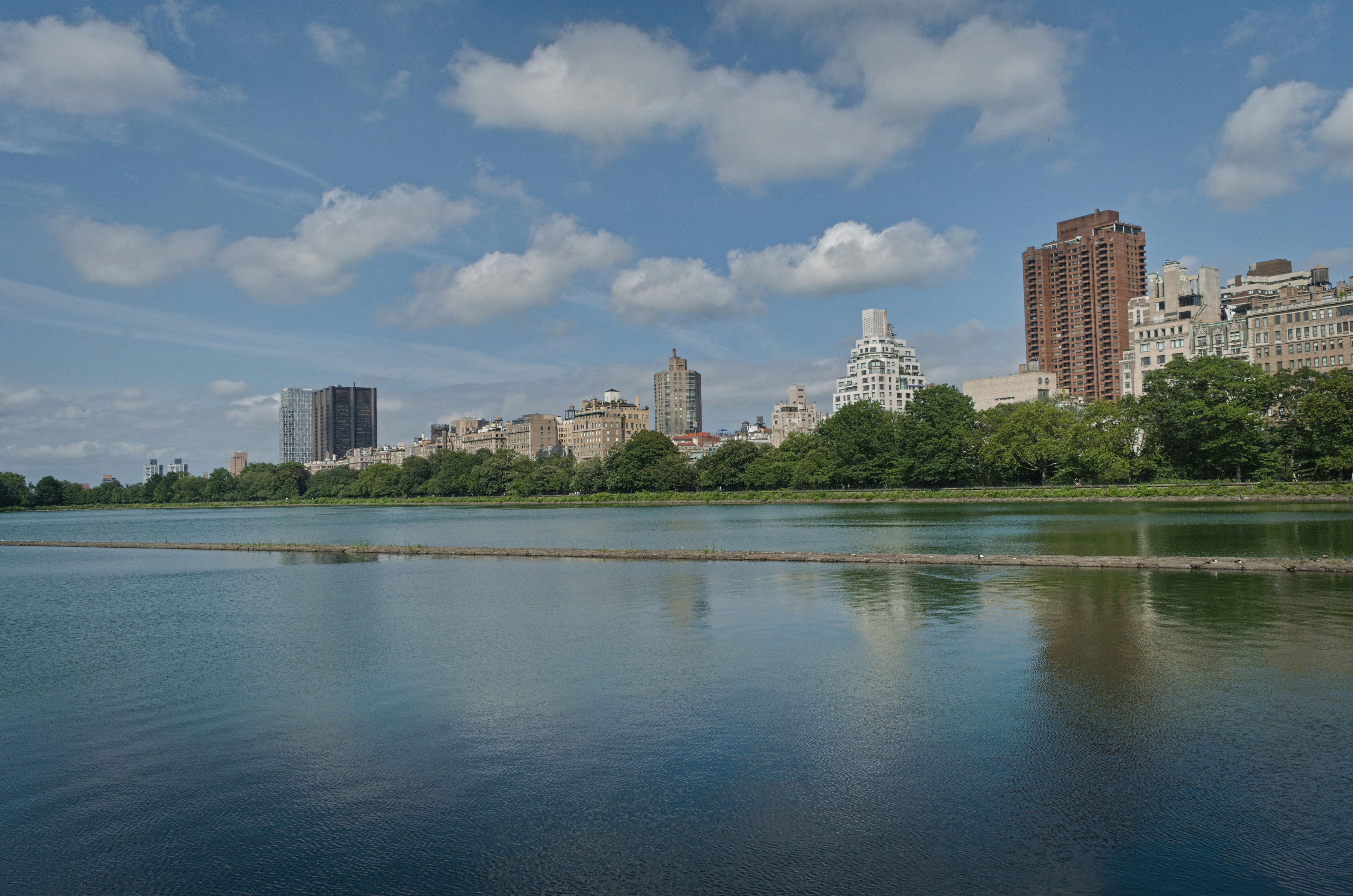 central park | City skyline reflected in a calm lake under clouds