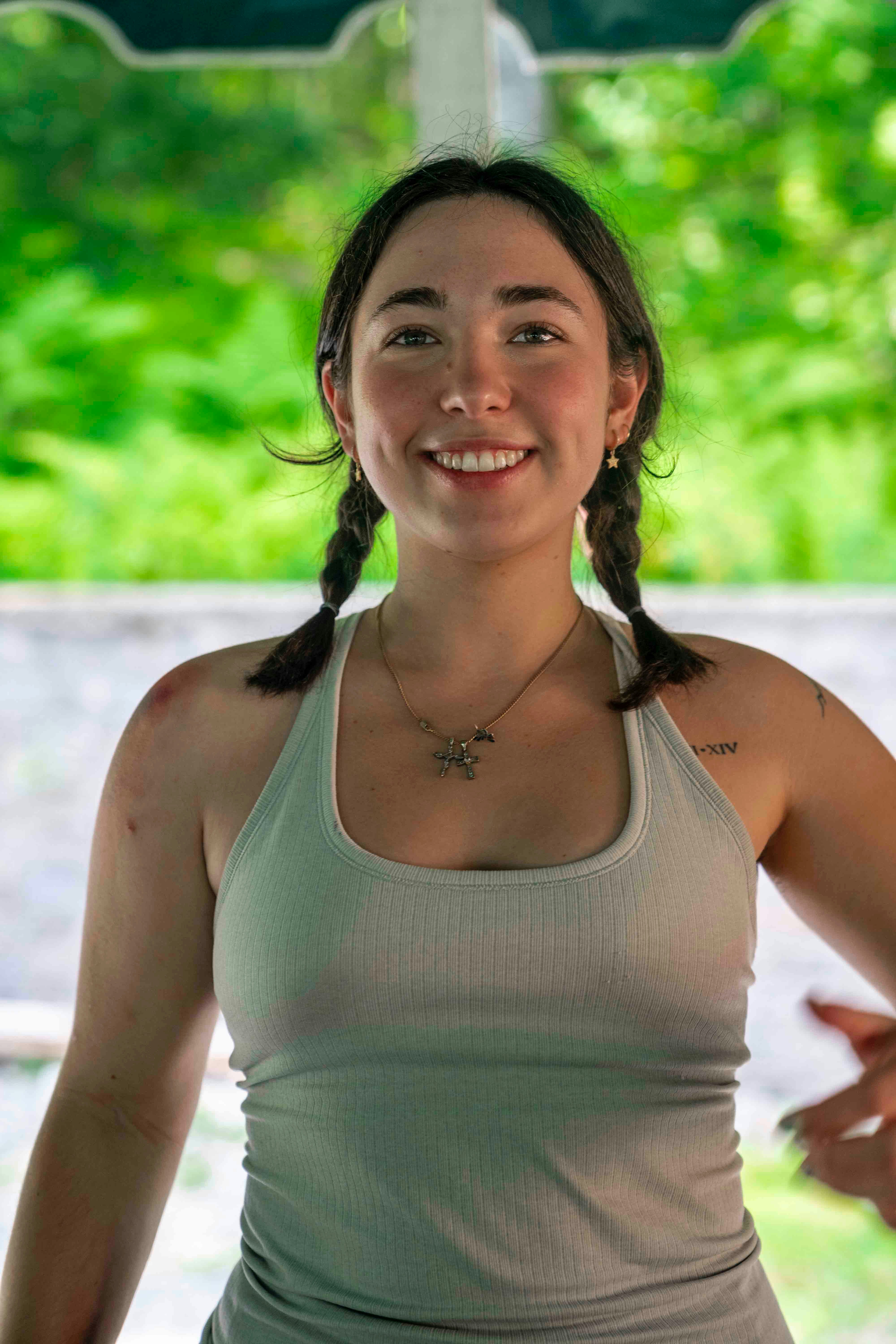 Young woman with braided pigtails smiles warmly smiling outdoors