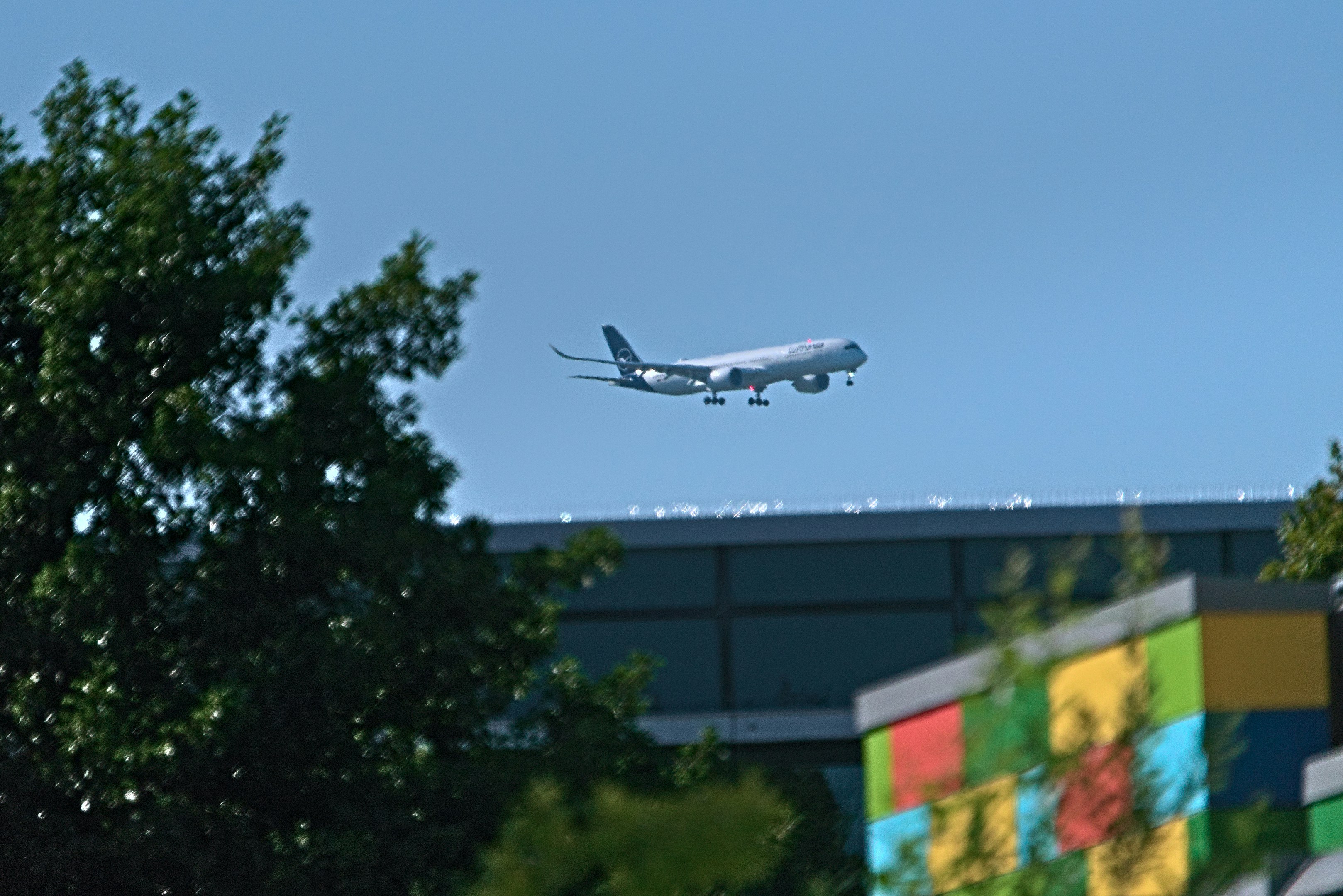 Airplane flying over a building and trees
