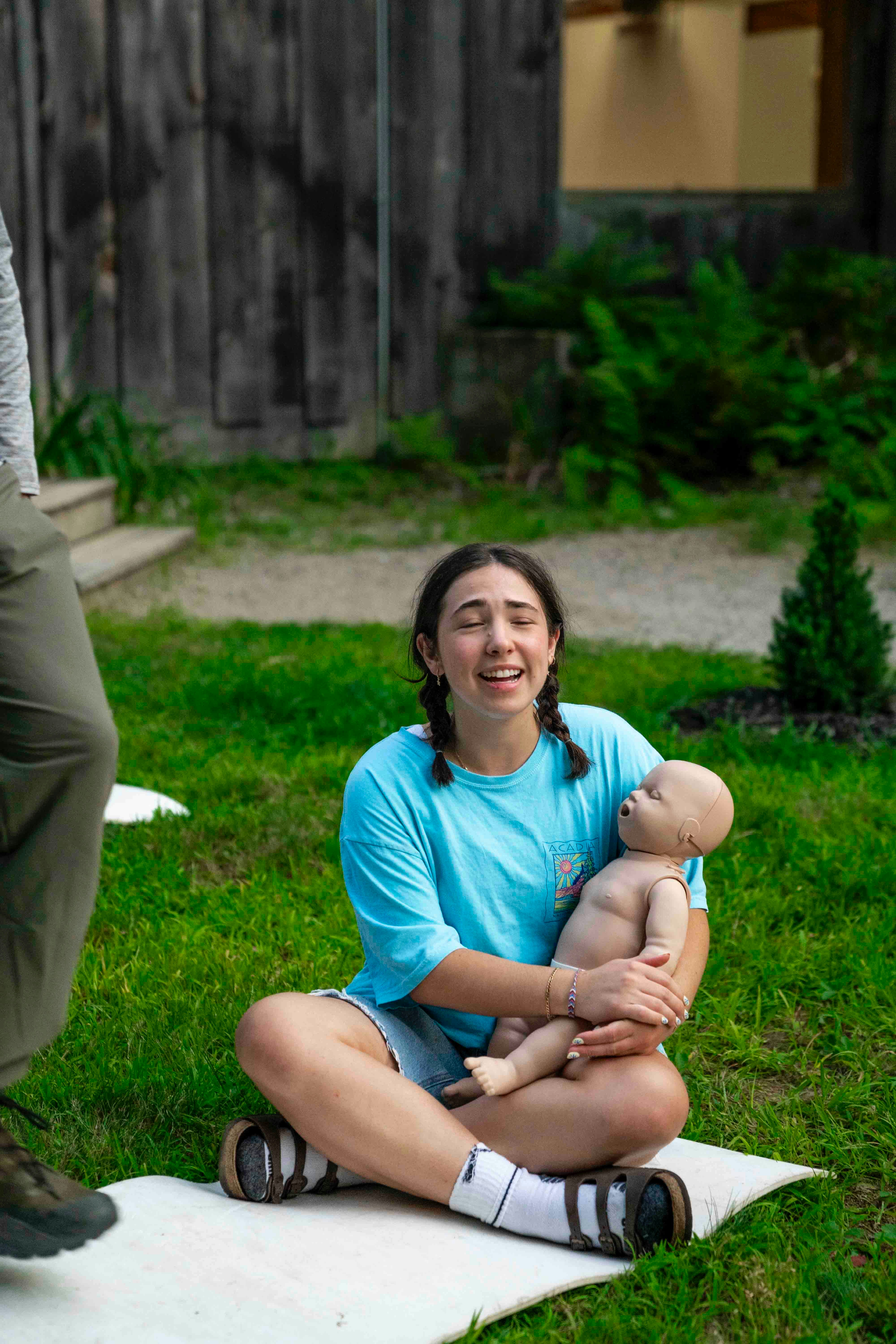 Lawnside Lullaby: A Girl in Blue with a Baby Doll on the Grass