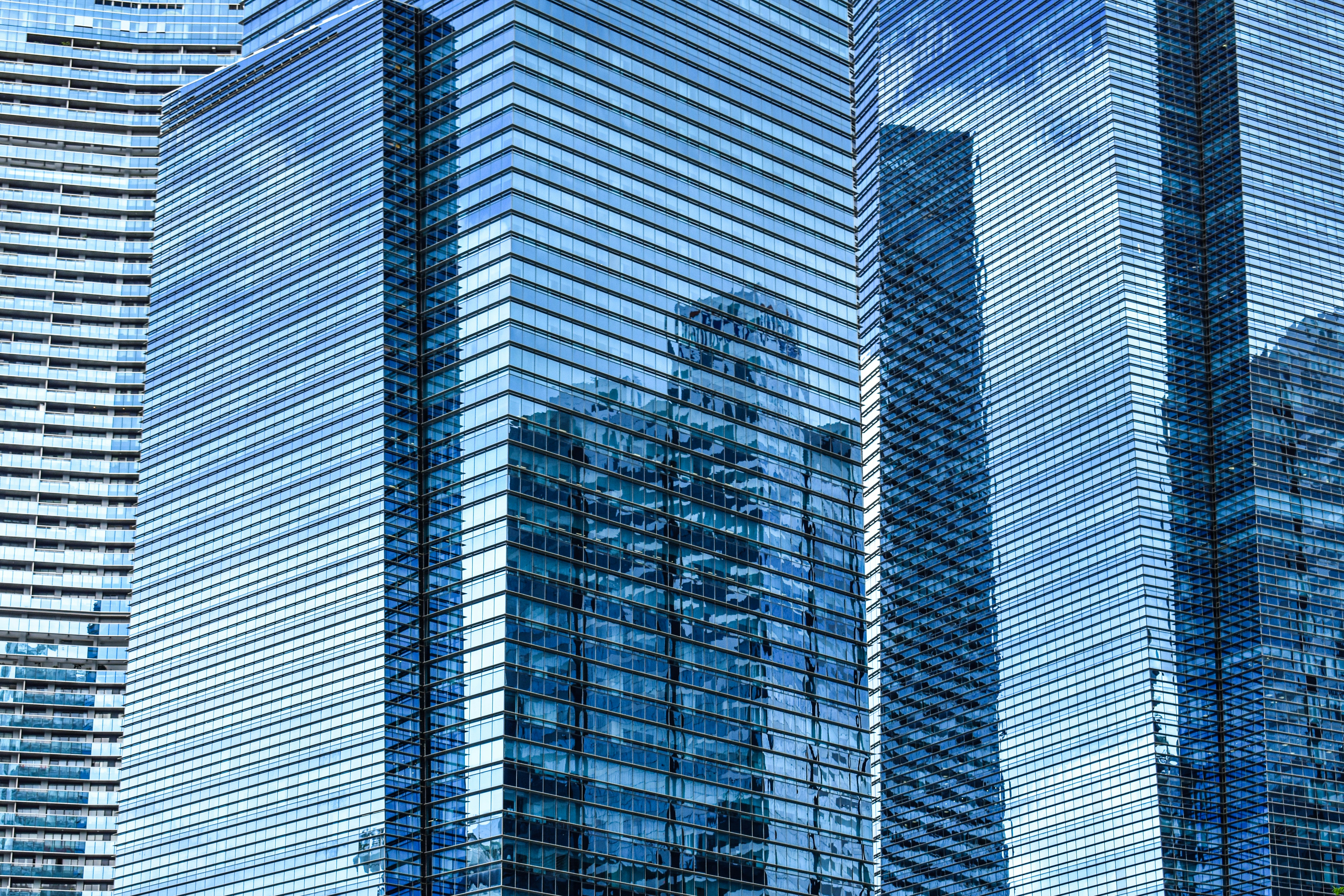 Skyscrapers with their glass facades reflect each other | Modern glass skyscrapers reflecting the sky