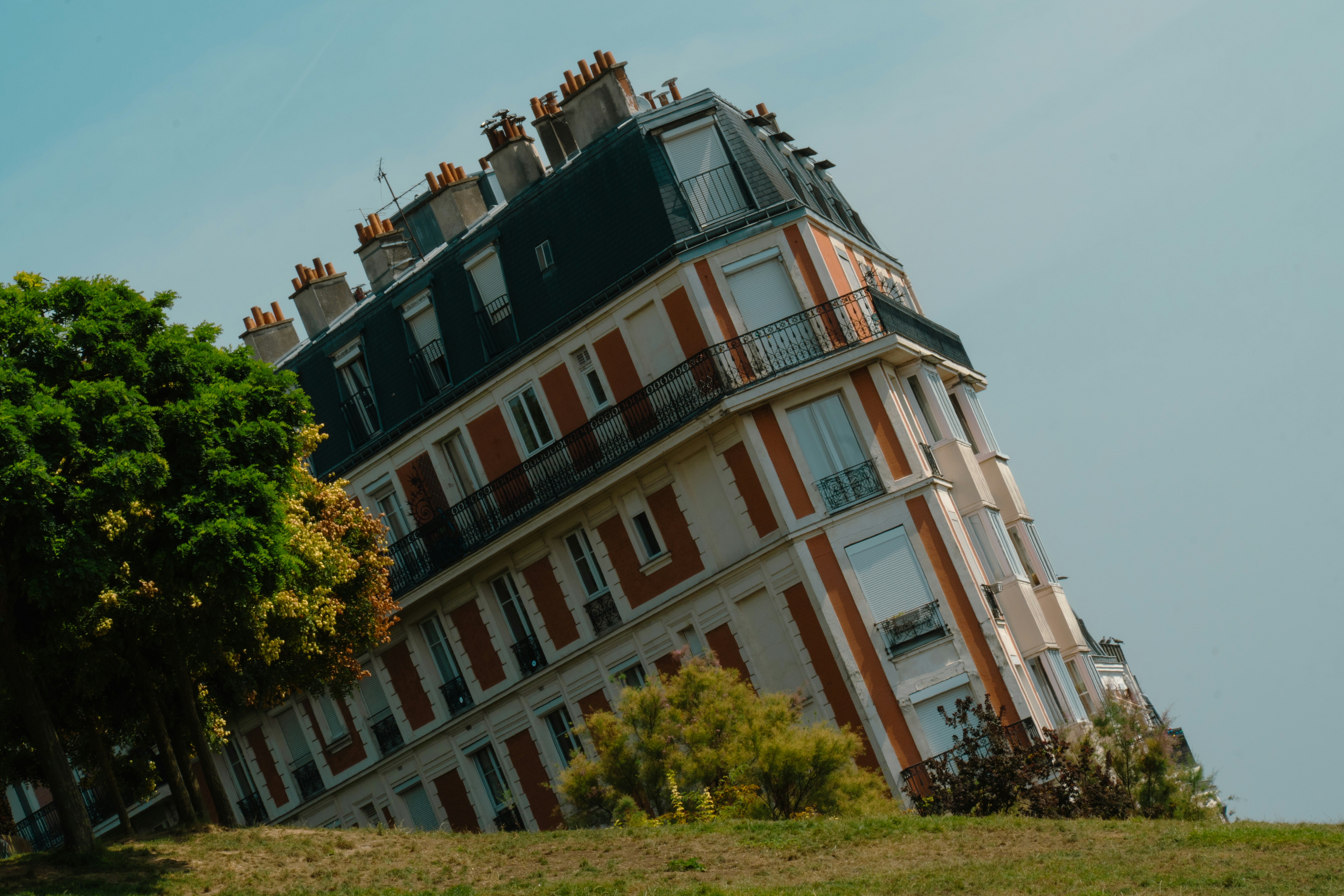 Building tilted on a grassy hill under a clear sky photo – Free ...
