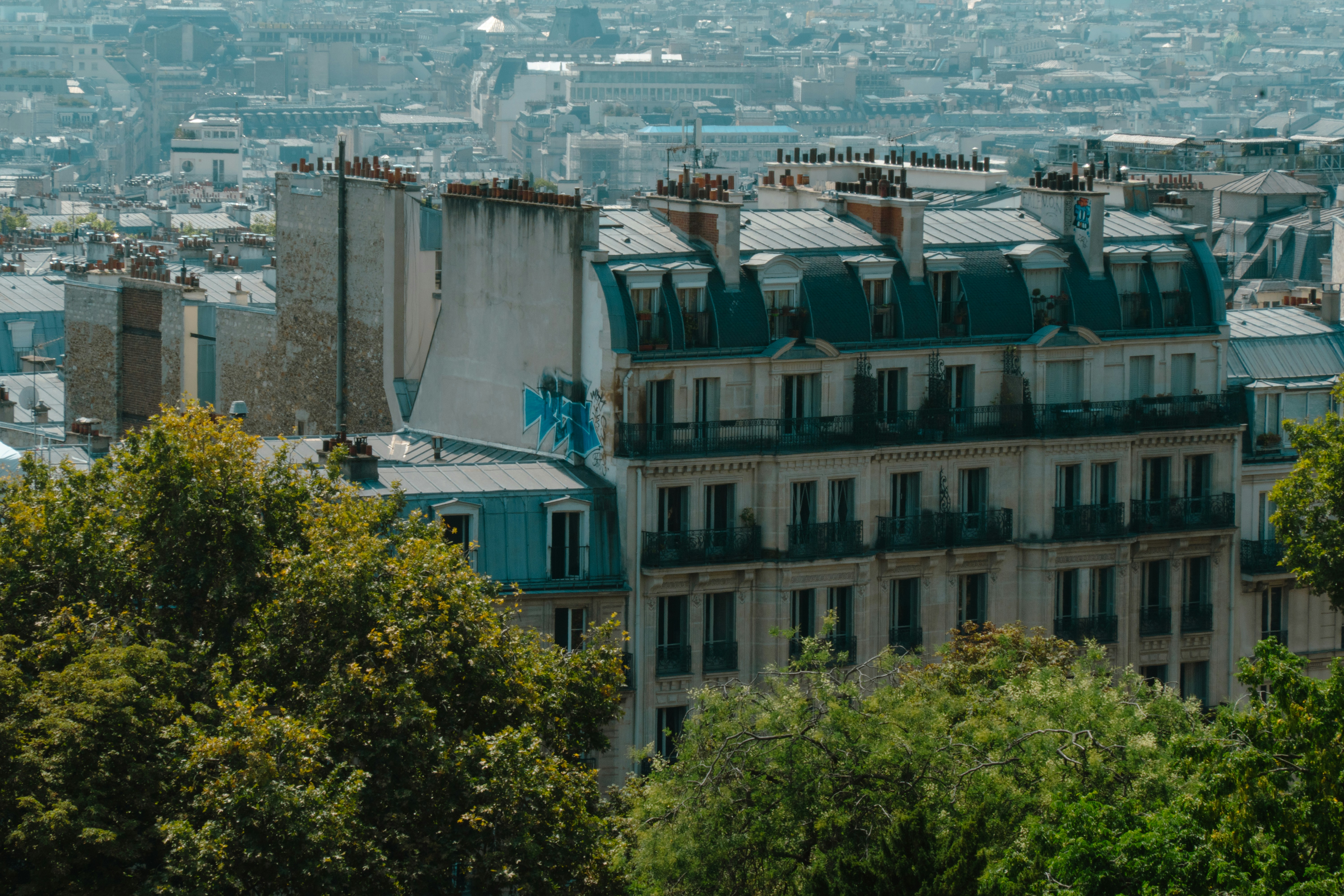 Historic Parisian building nestled among lush greenery, showcasing classic architecture against a backdrop of the sprawling cityscape.