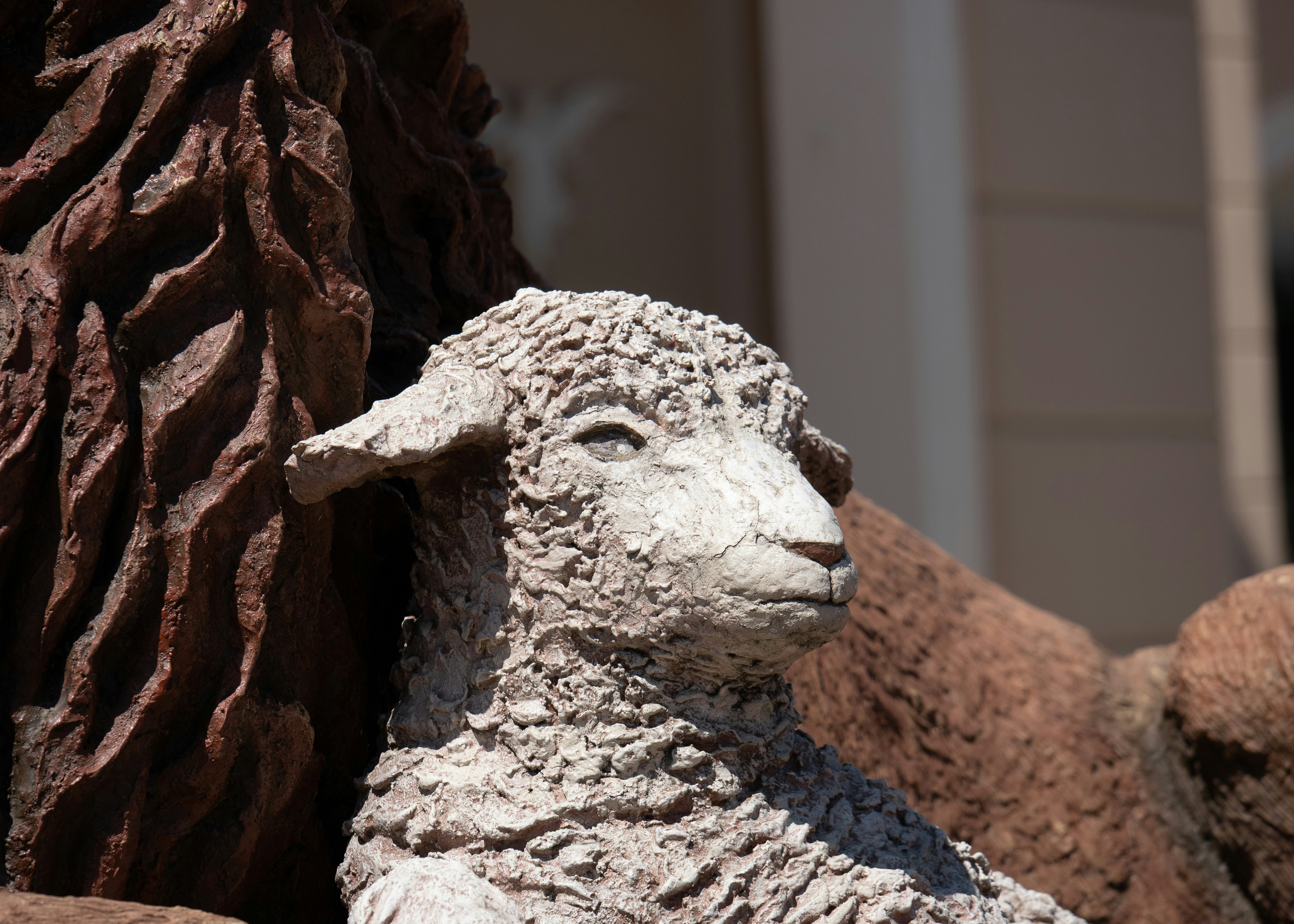 White Sheep Sculpture Emerges from a Rugged Stone Mosaic