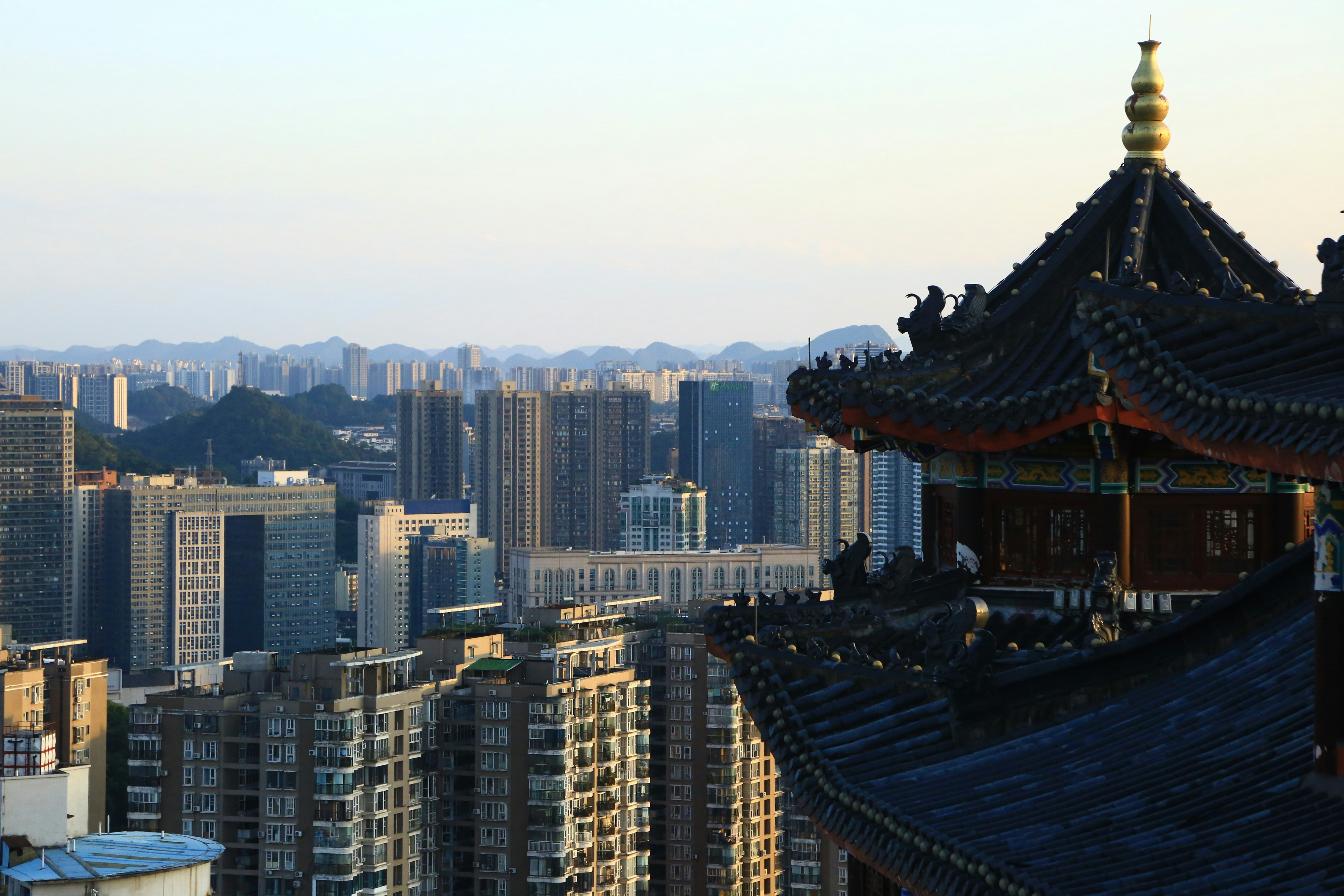 Traditional pagoda overlooks modern cityscape at dusk