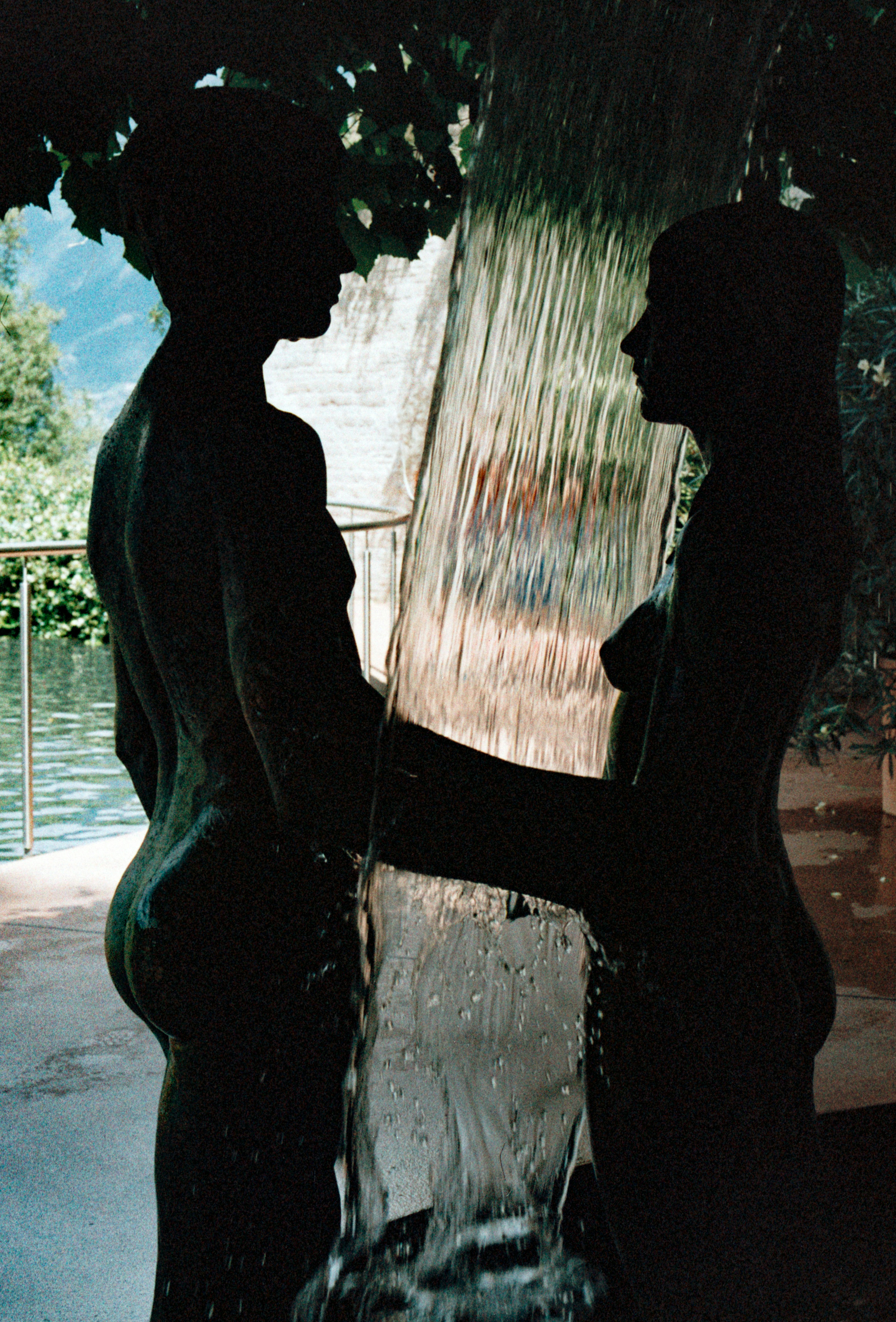 Silhouettes of a couple standing under a waterfall