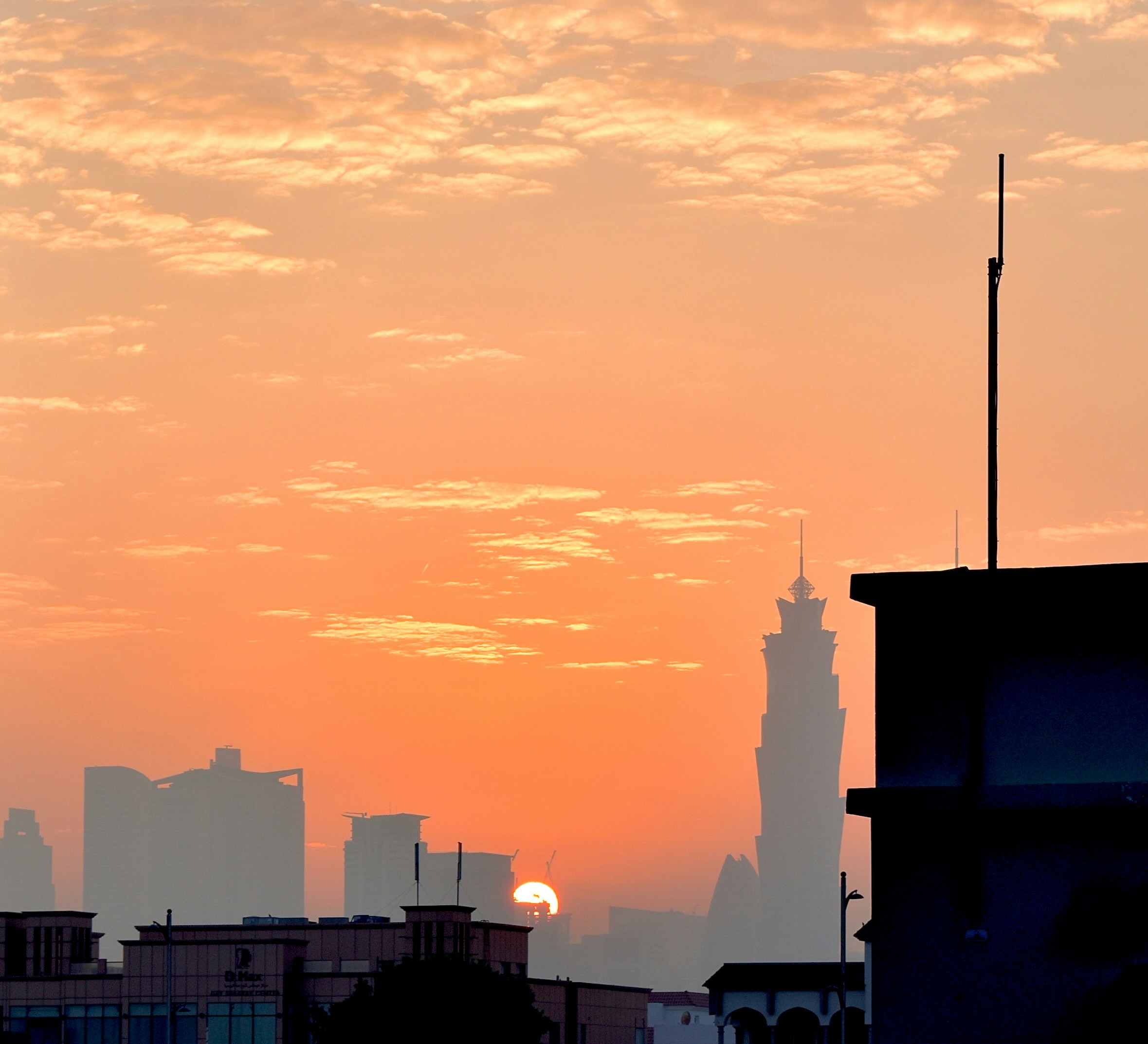 City sunrise with orange sky and few clouds | City skyline silhouetted against an orange sunrise sky
