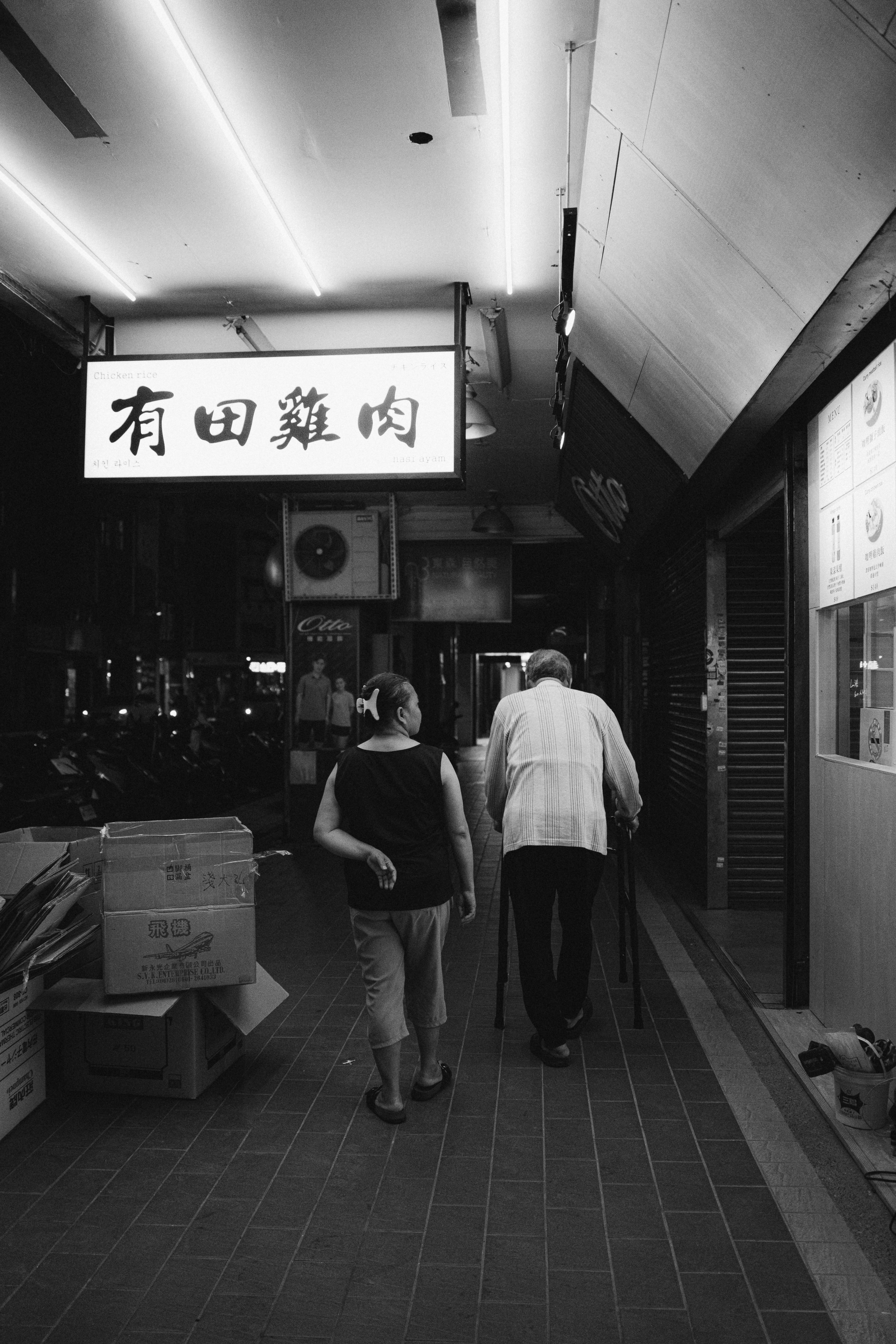 Elderly couple walks down a street at night.