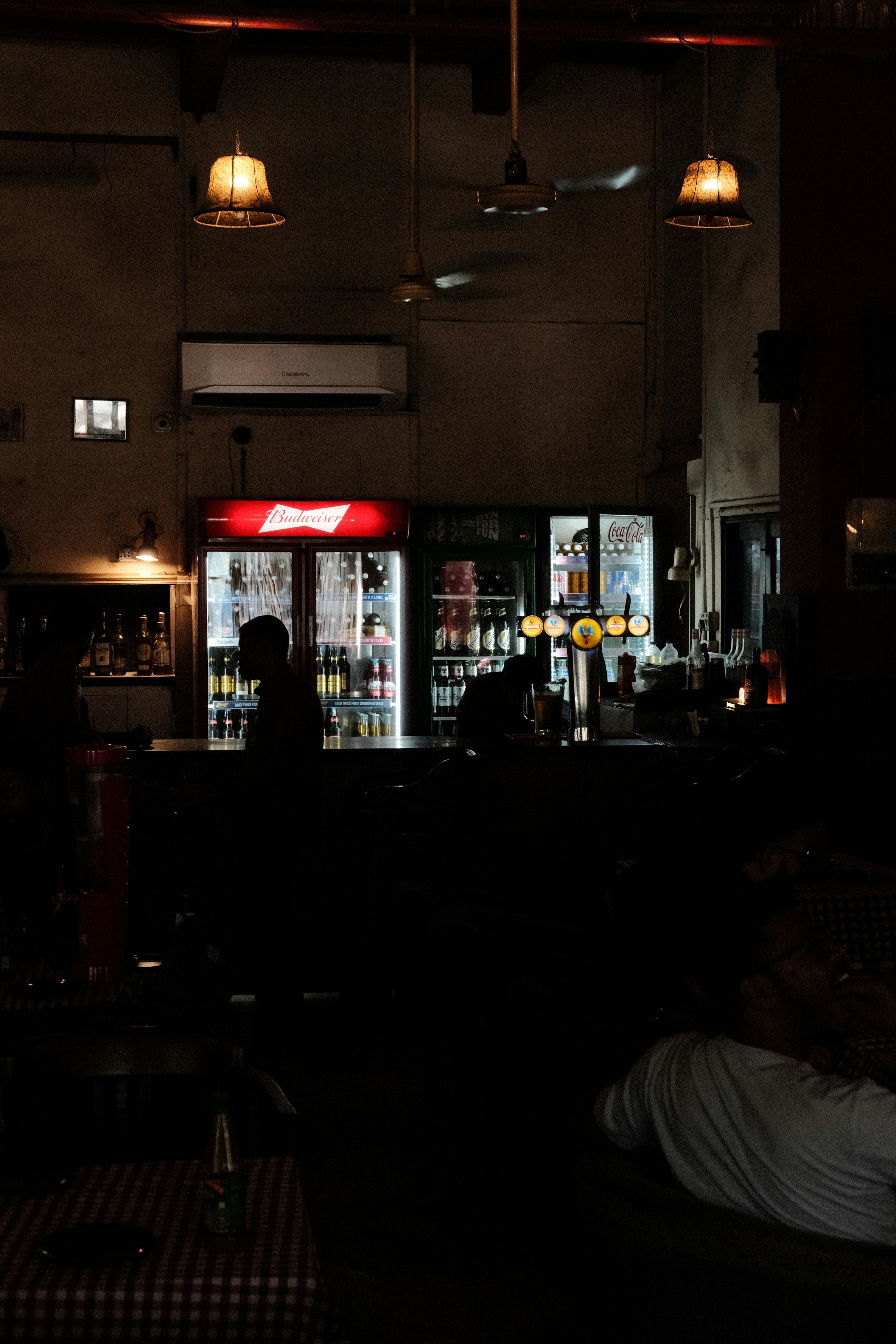 People at a dimly lit bar with refrigerators