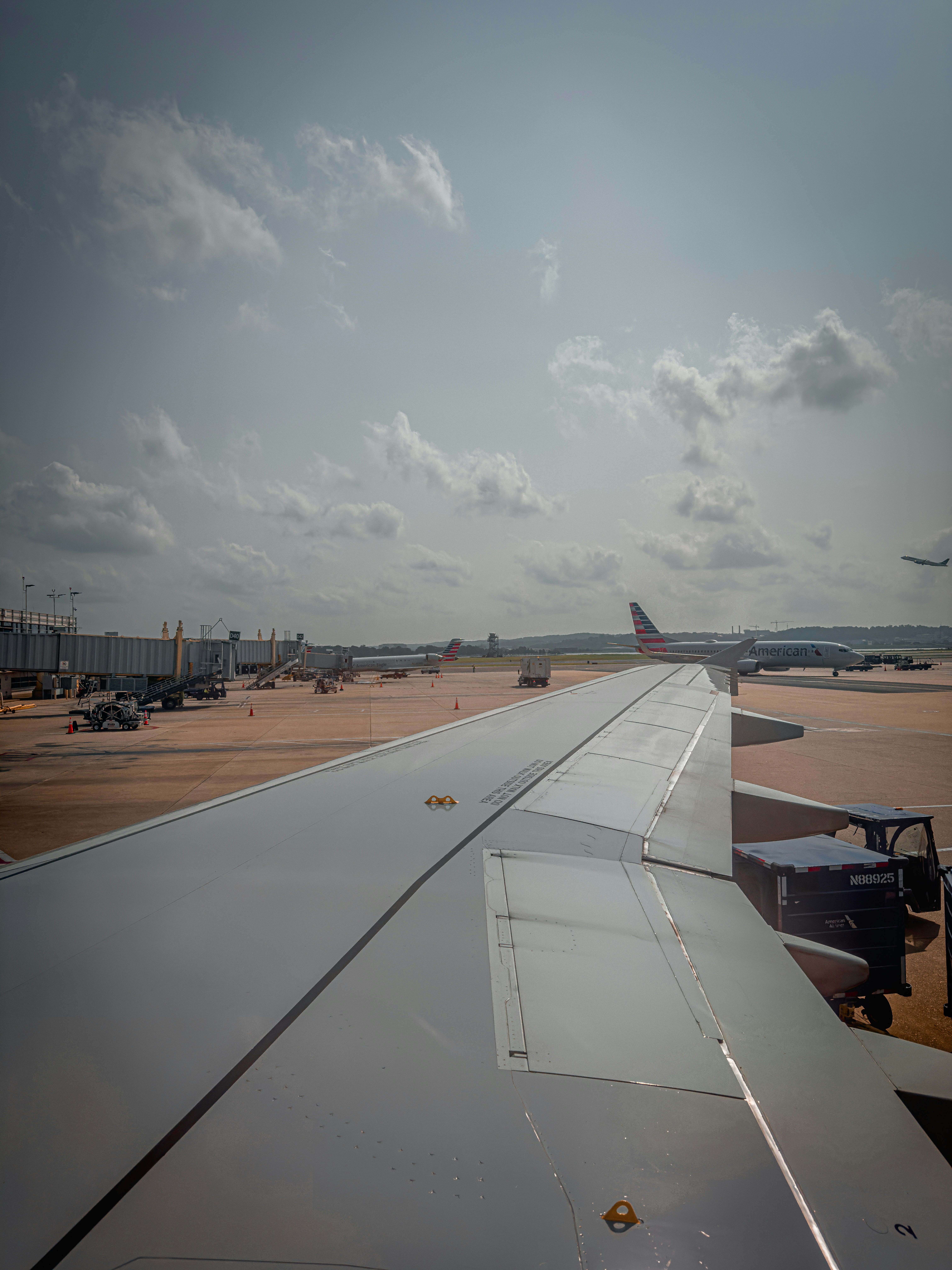 Airplane wing on tarmac with other planes and jet bridges